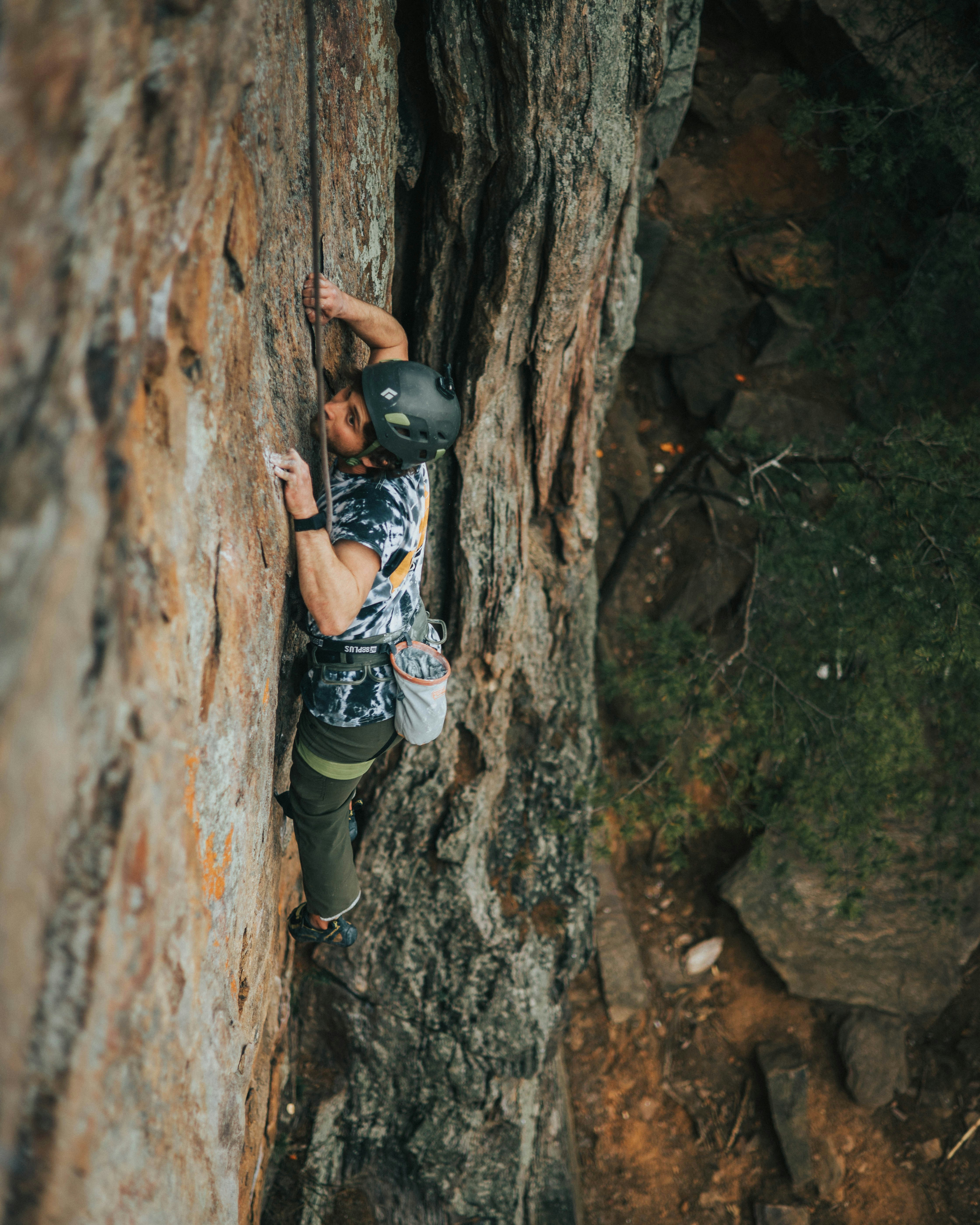Climber scaling a rugged rock face, showcasing determination and skill in a natural setting.