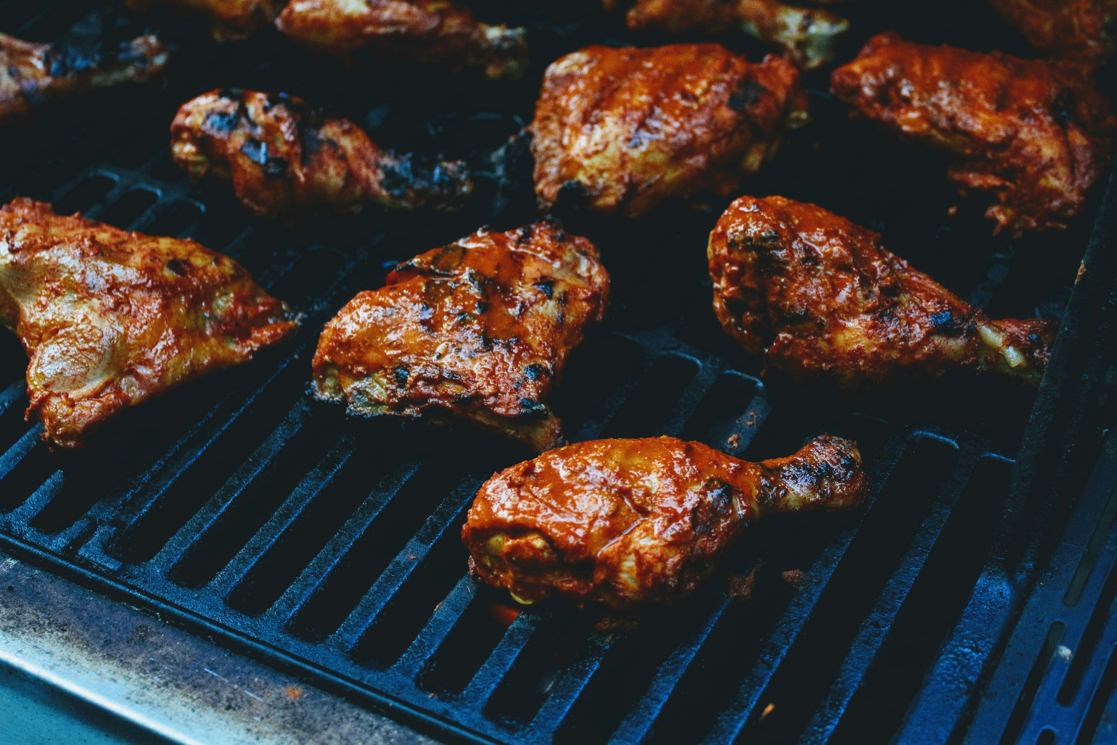 Grilled chicken pieces with a rich, smoky glaze resting on a barbecue grill, showcasing the art of outdoor cooking.