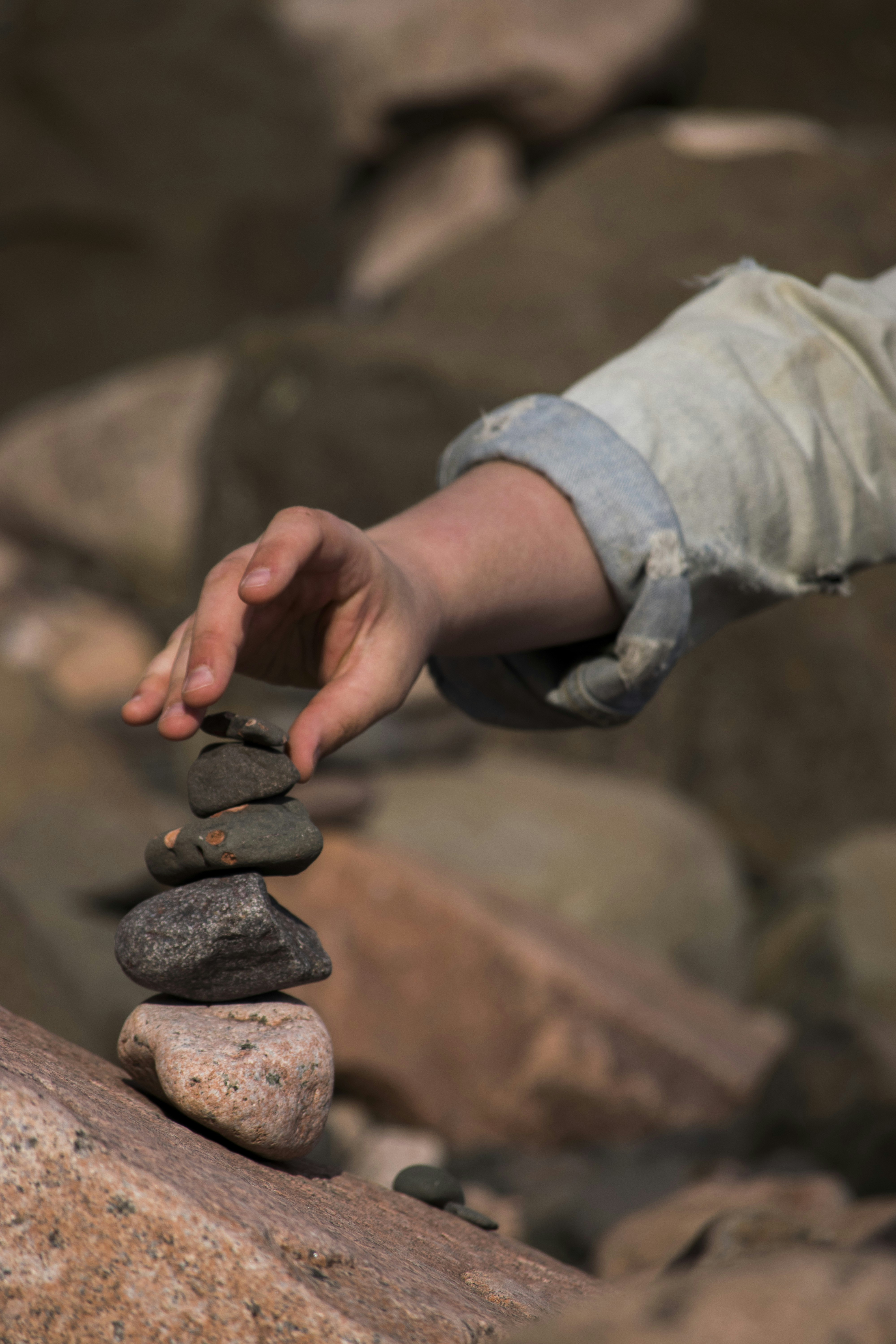 Balance in Stones: A Hand Steadily Balancing Pebbles on a Rough Surface