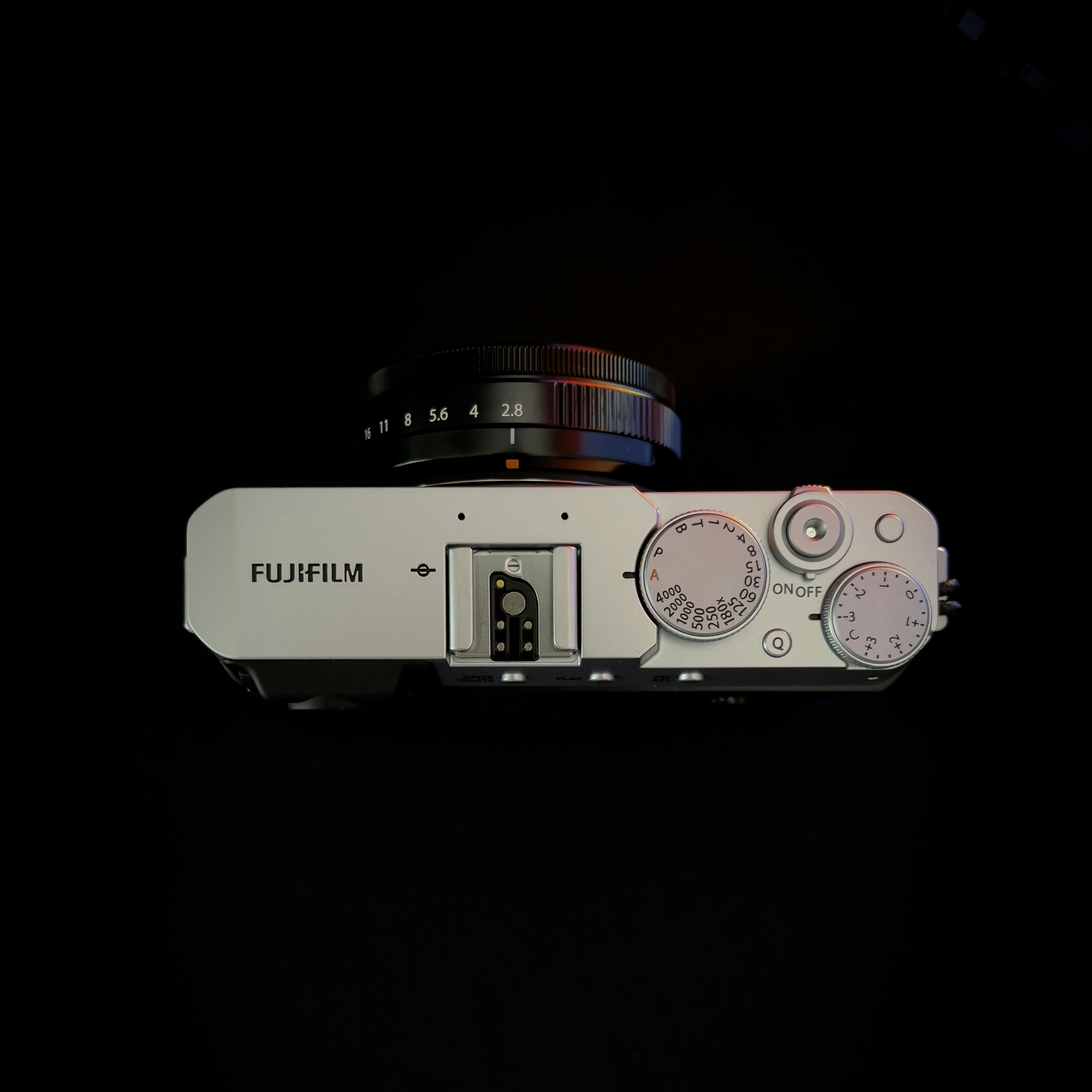Top view of a Fujifilm camera showcasing its intricate dials and sleek design against a dark background.
