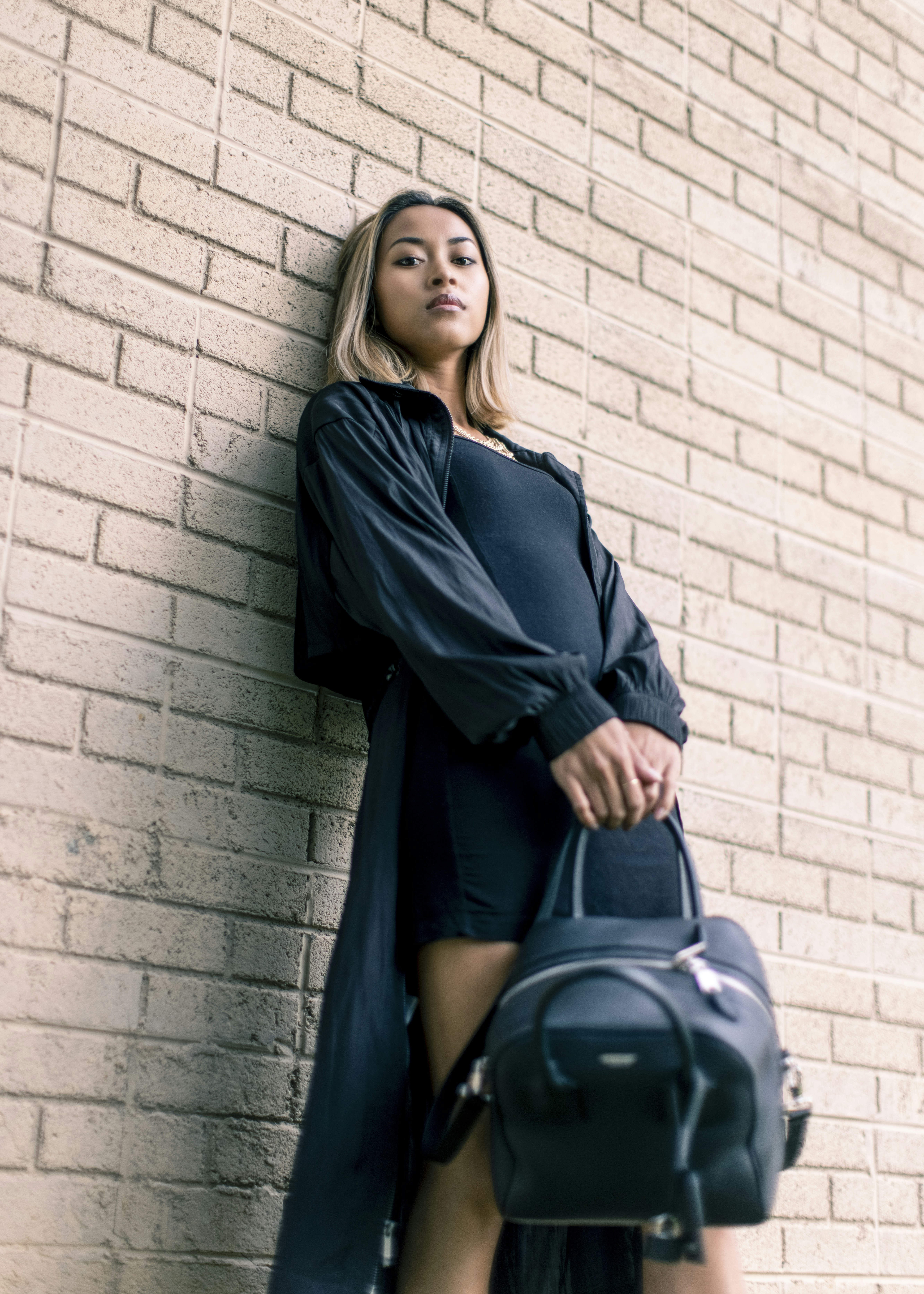 Urban Muse: A Confident Pose by the Brick Wall