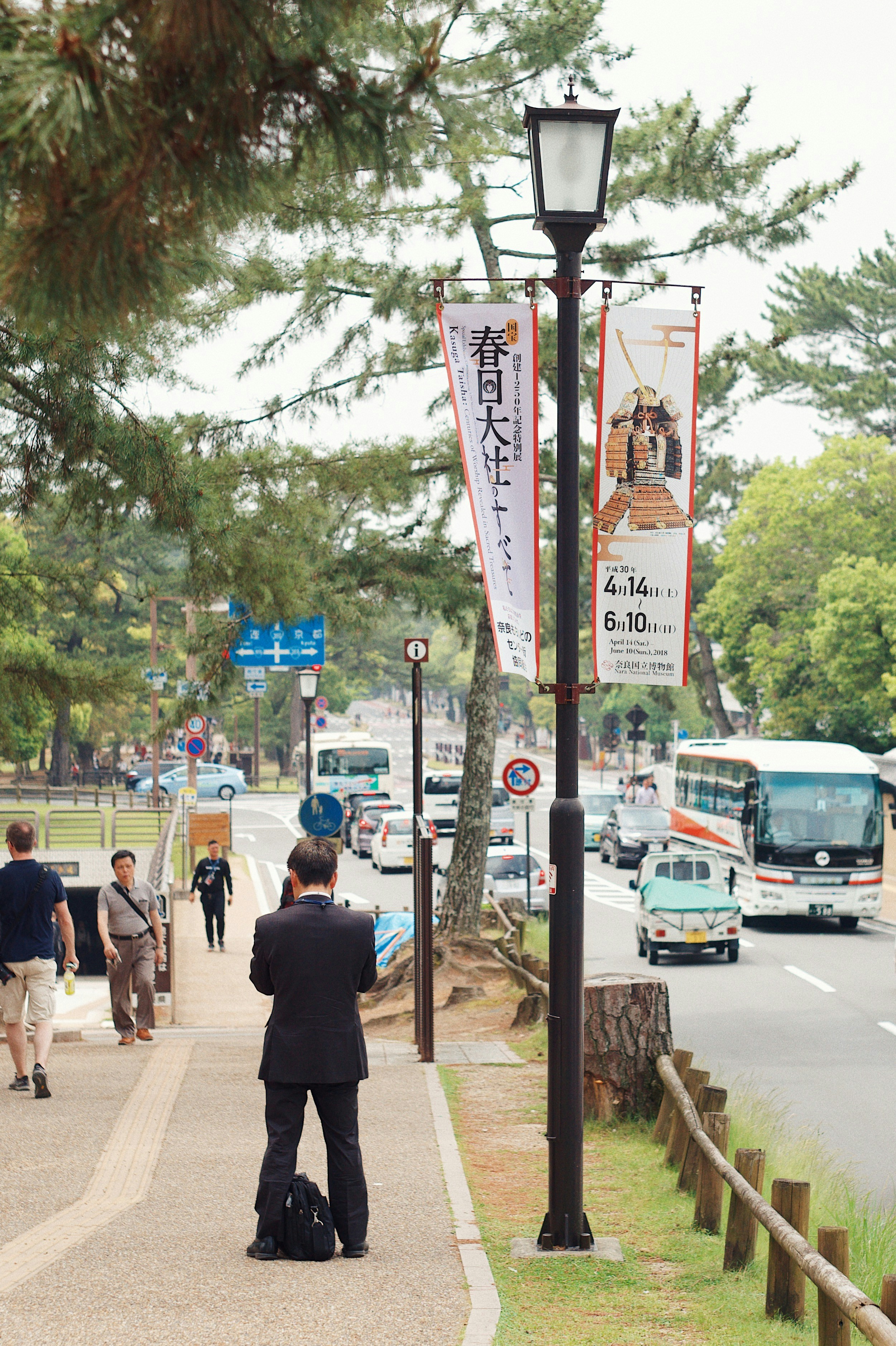 Between Banners and Bus Lanes: A Suited Photographer Captures a City Moment