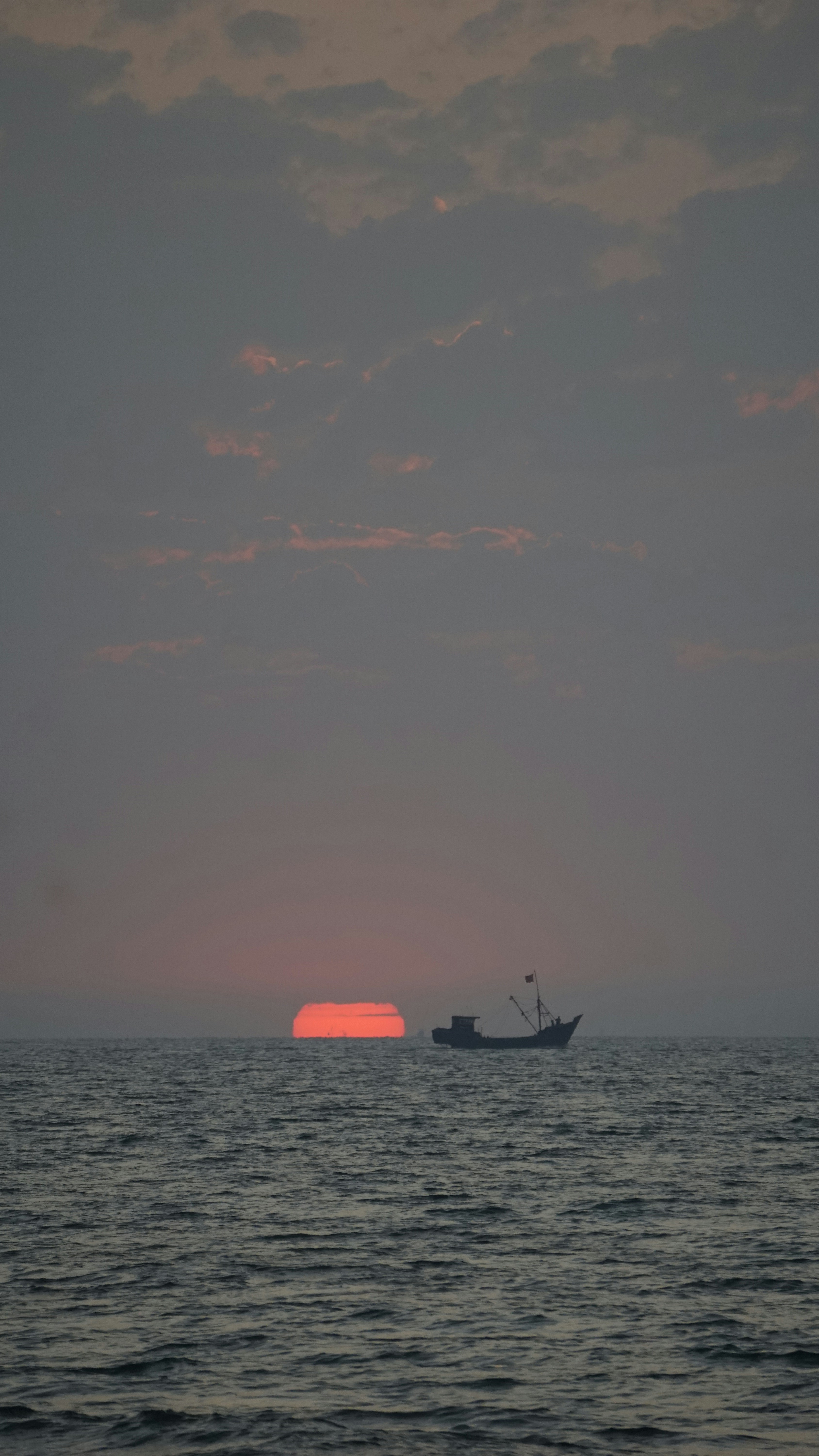 Horizon Ember: Fishing Boat Silhouette at Dusk over a Quiet Sea