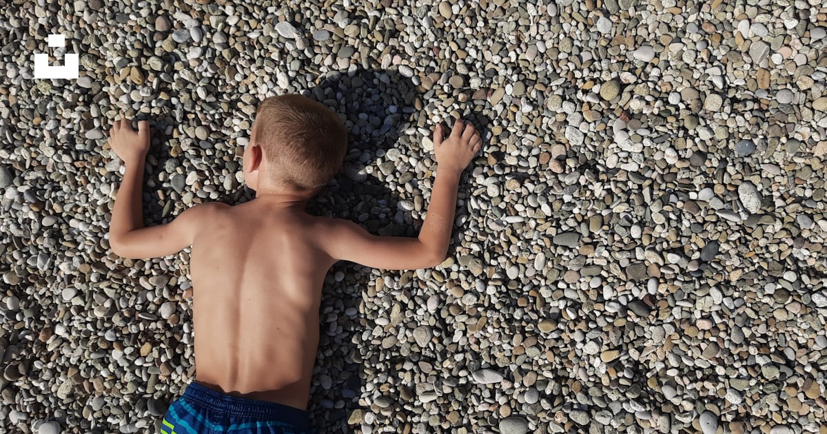岩場に横たわるトップレスの少年の写真 Unsplashの無料人写真