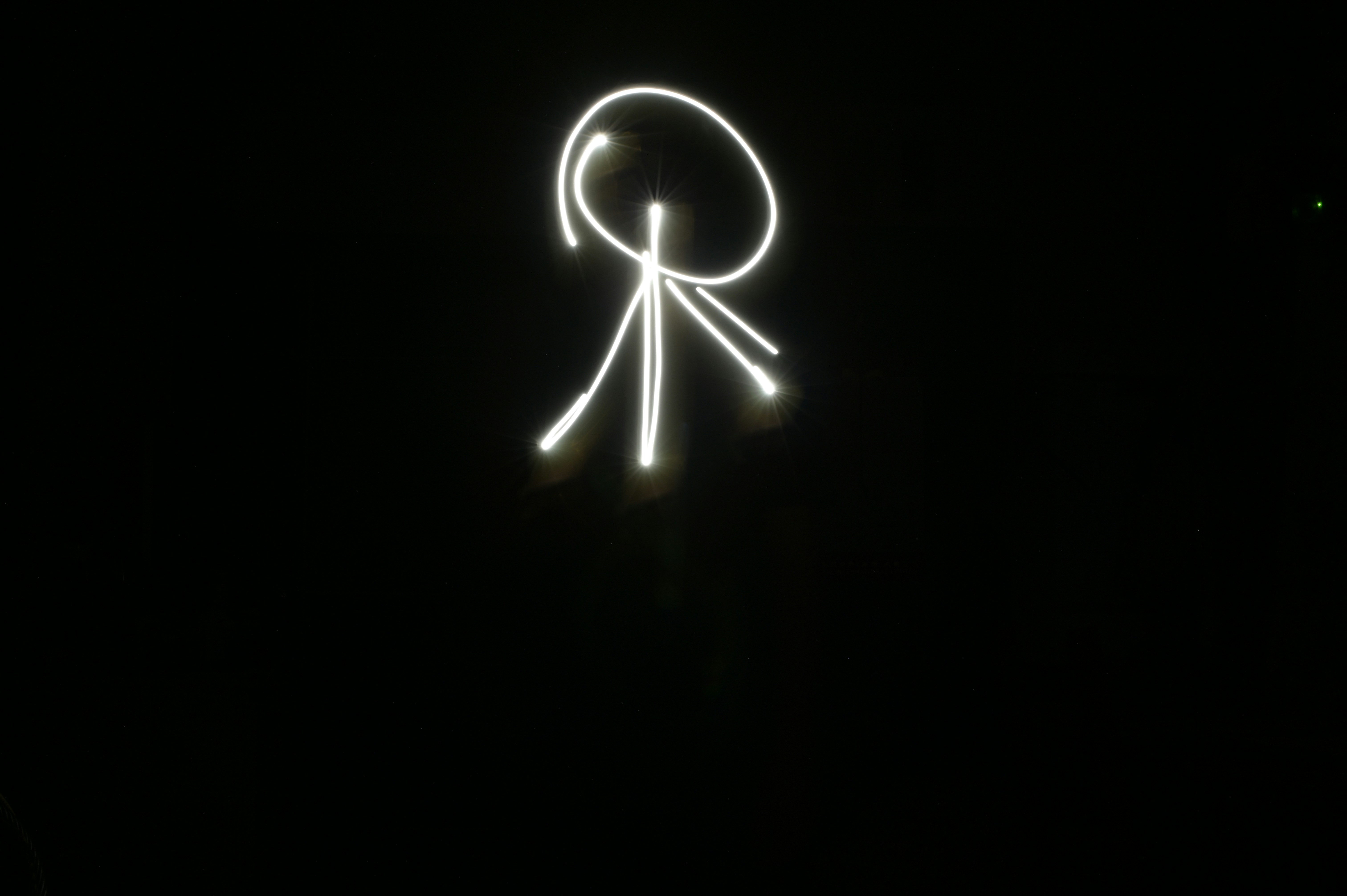 Abstract light trails forming a stylized letter in a dark environment.