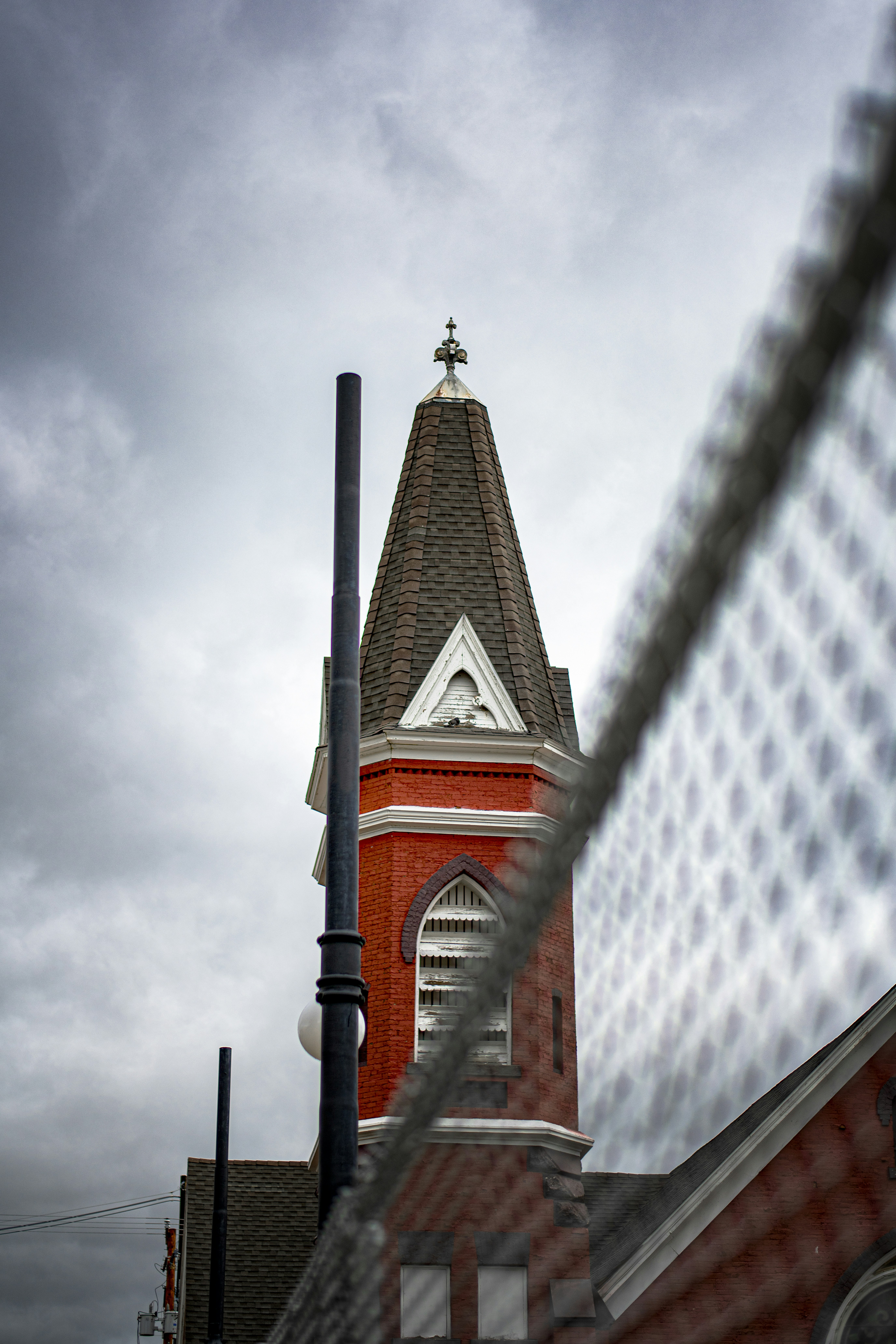 Chimed Spire Behind a Chain-Link Veil