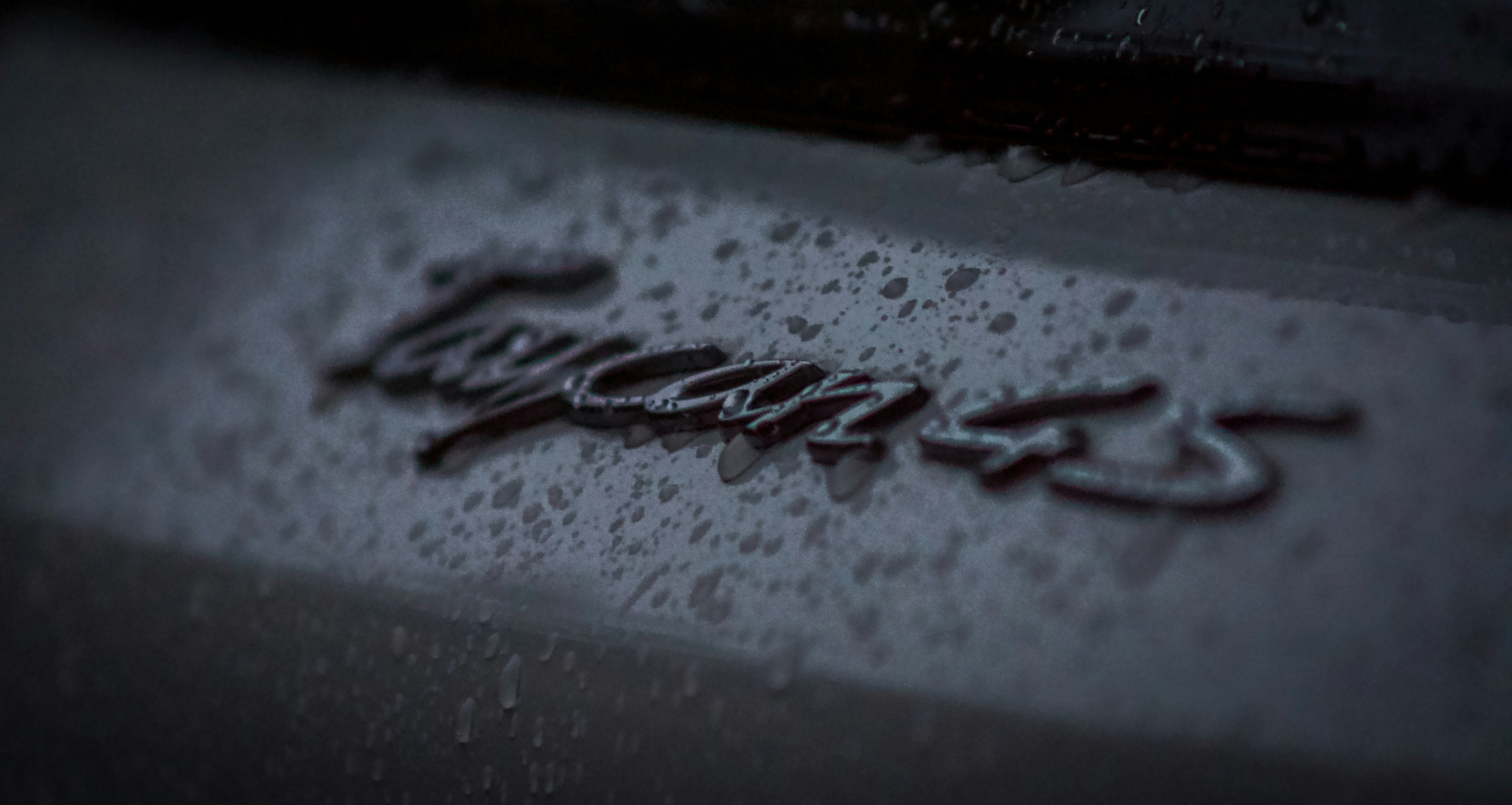 Rain-Kissed Emblem: Close-Up of a Glossy Car Badge