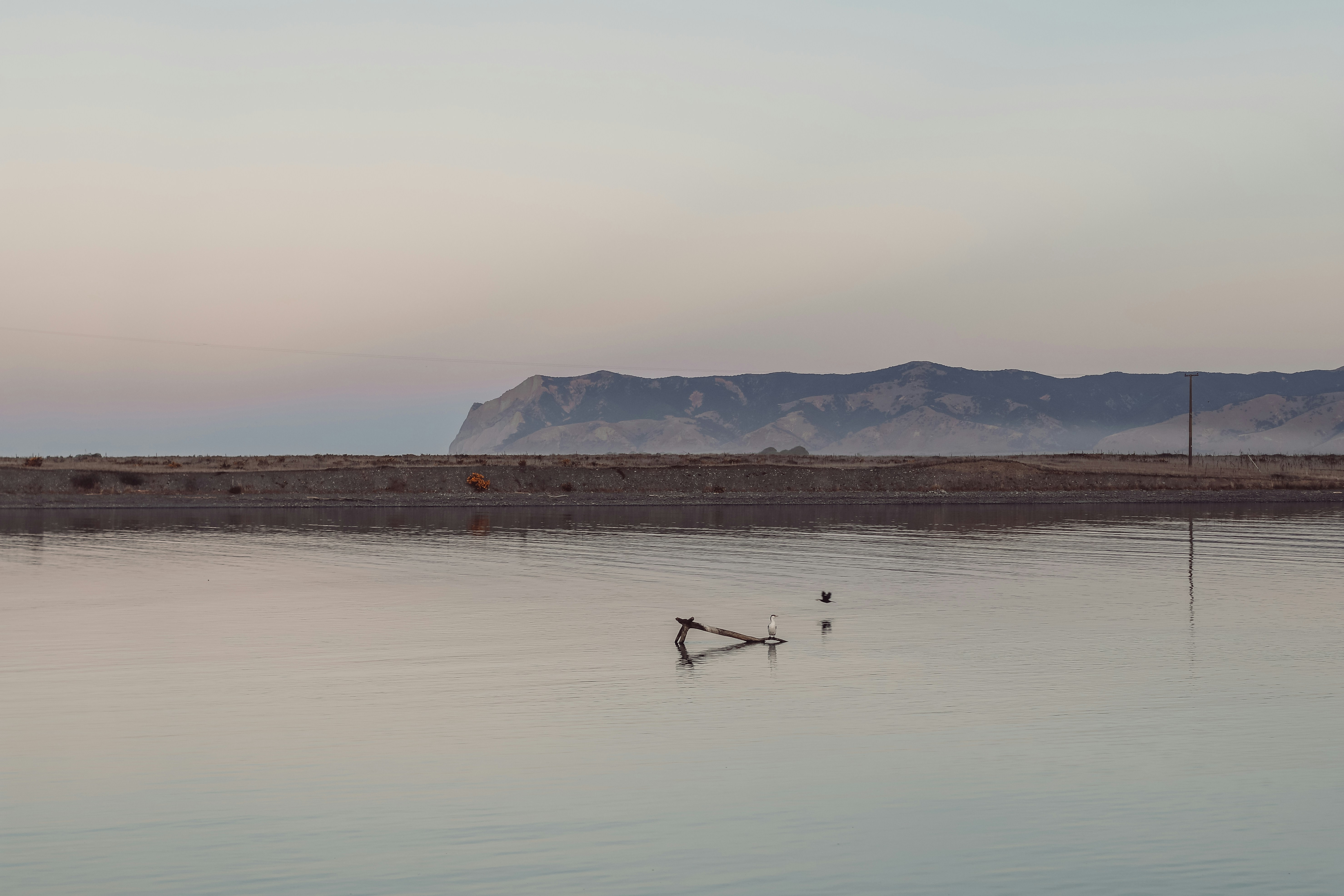Lone Rowboat on a Glassy Lake Beneath a Cliff-Laced Horizon
