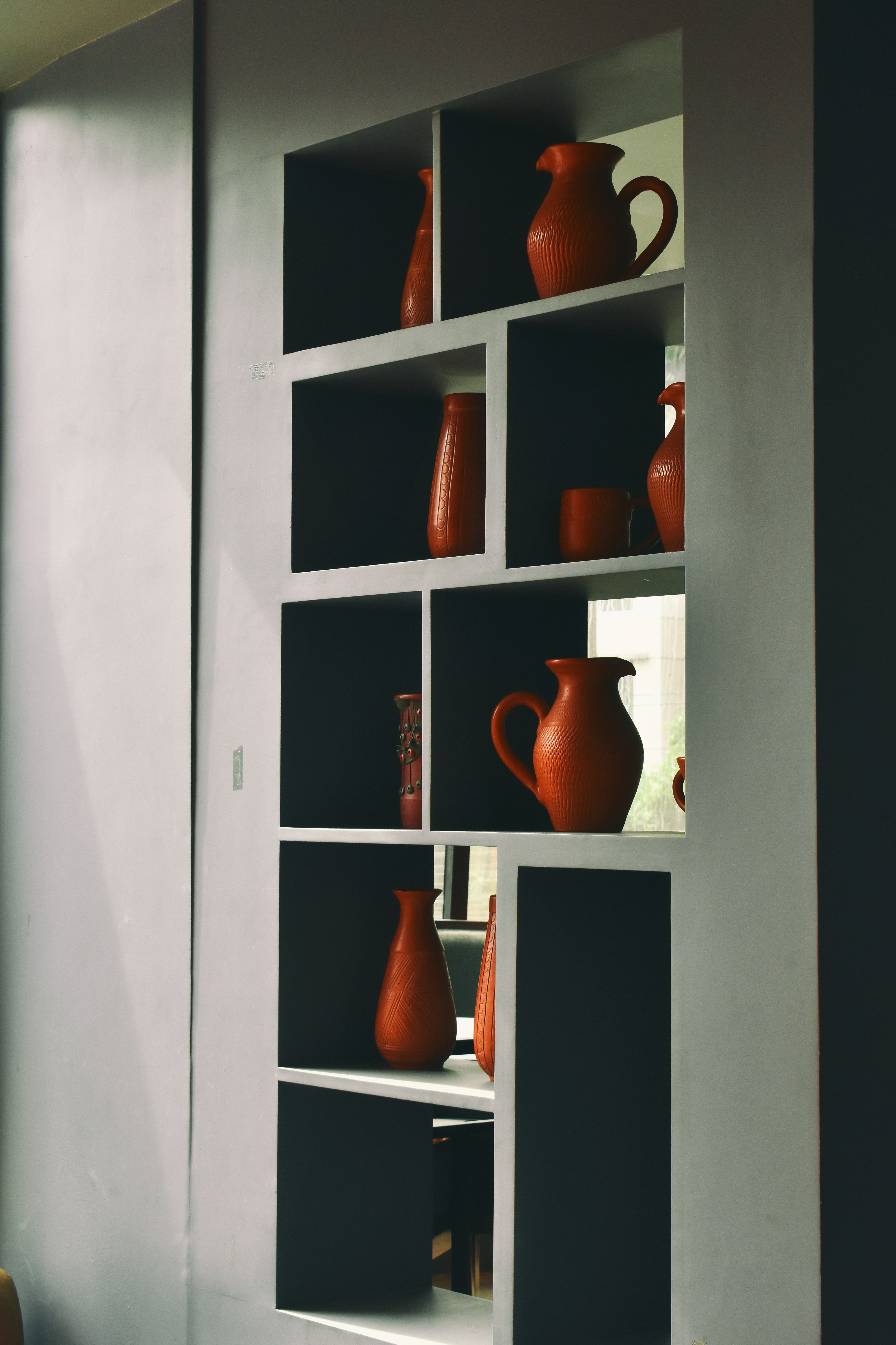 Crimson Vessels Nestled in a Modern Grid Shelf