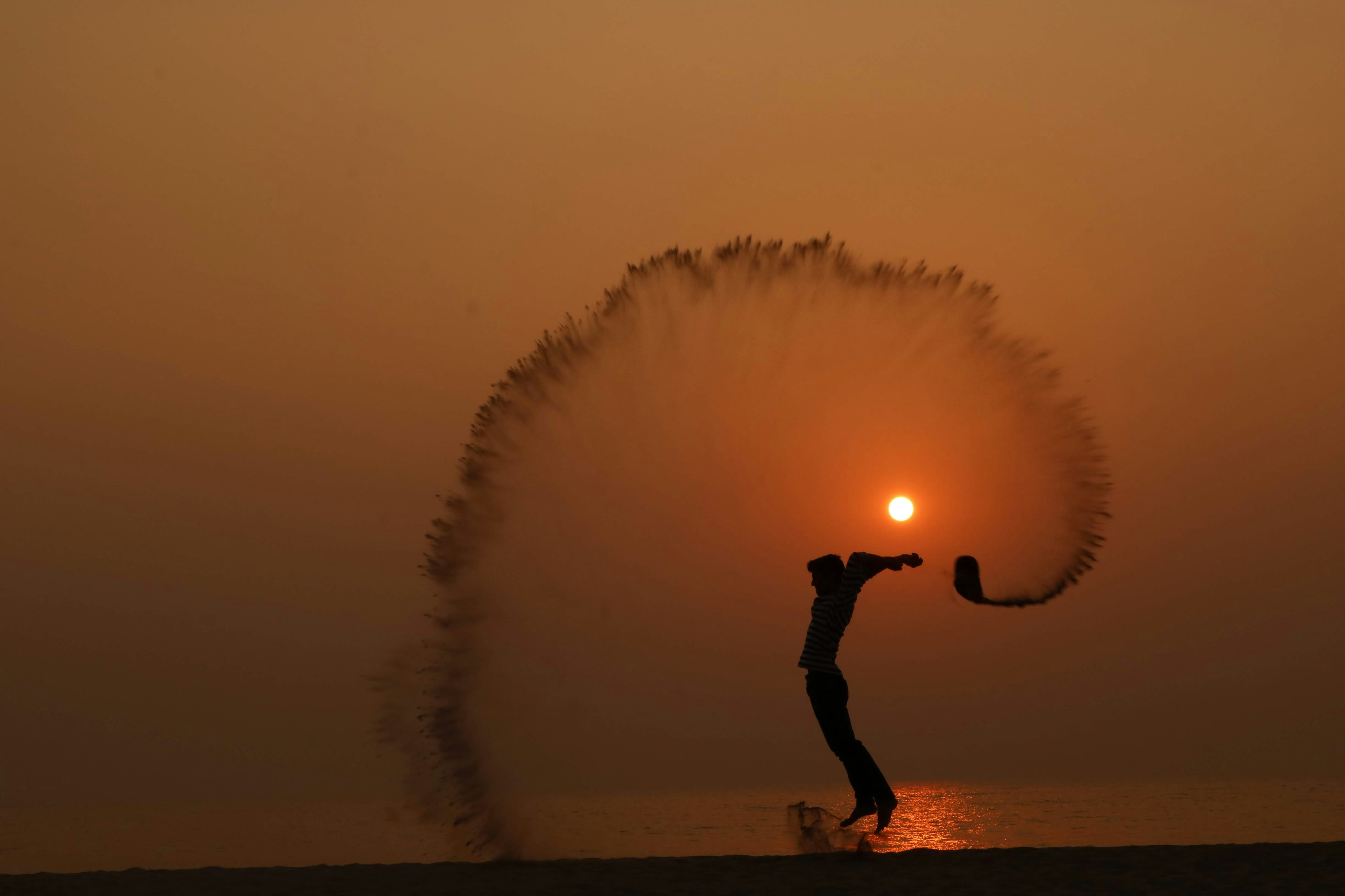 Sunset Spin: A Dancer Conjures a Powder Ring Along the Quiet Shore