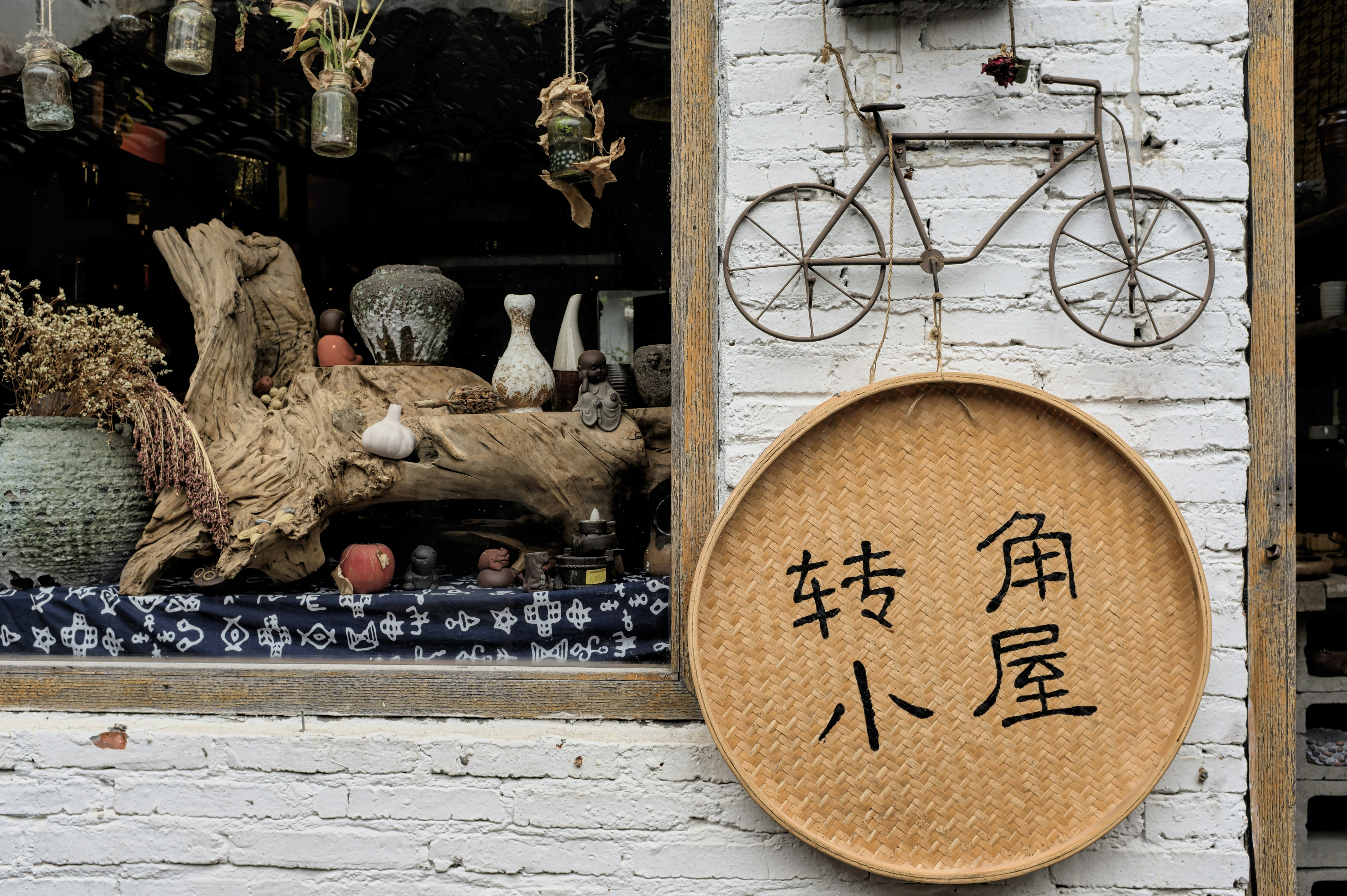 A charming storefront featuring a variety of handcrafted pottery and rustic decor, accented by a decorative woven sign. 