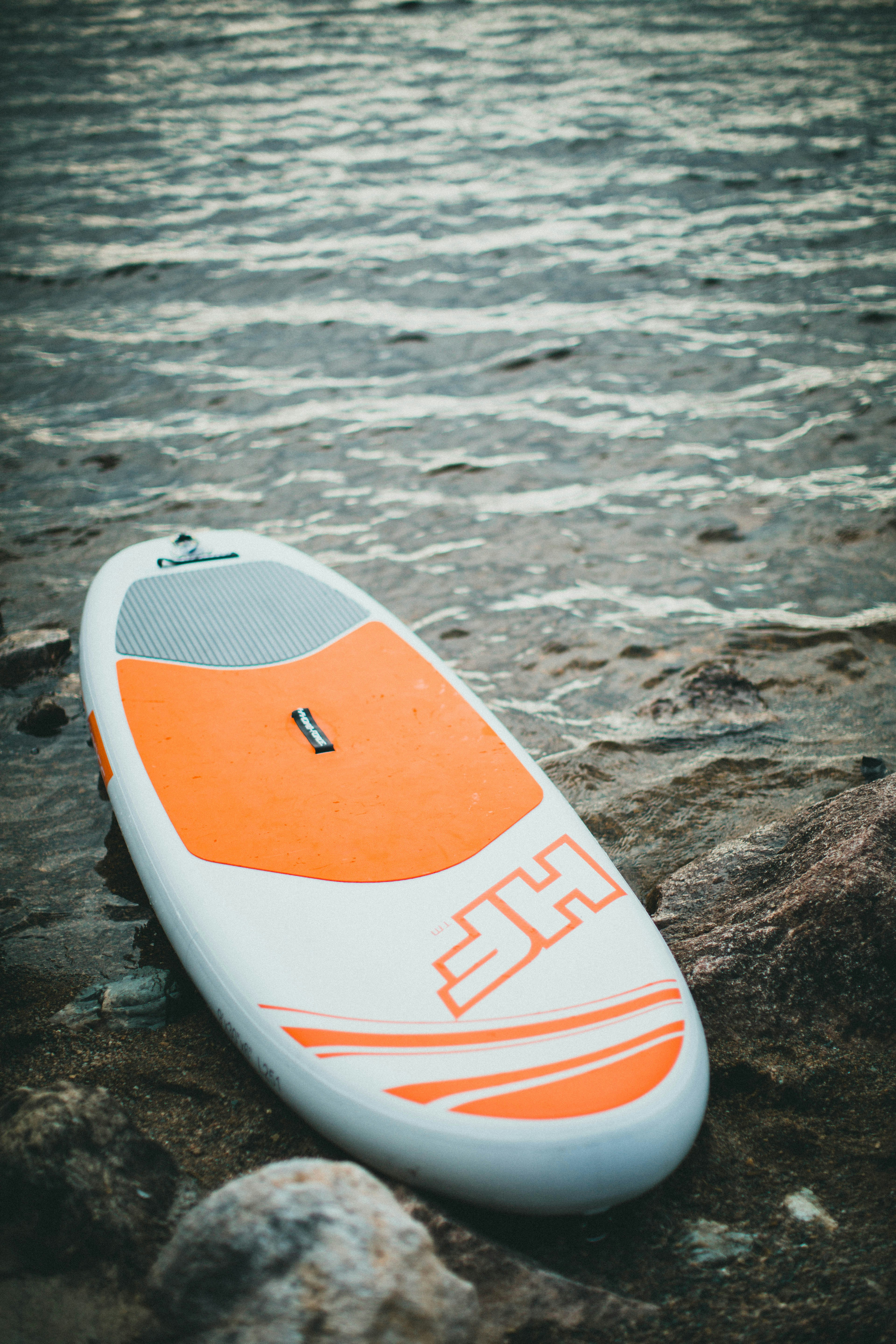 white and orange surfboard on beach during daytime