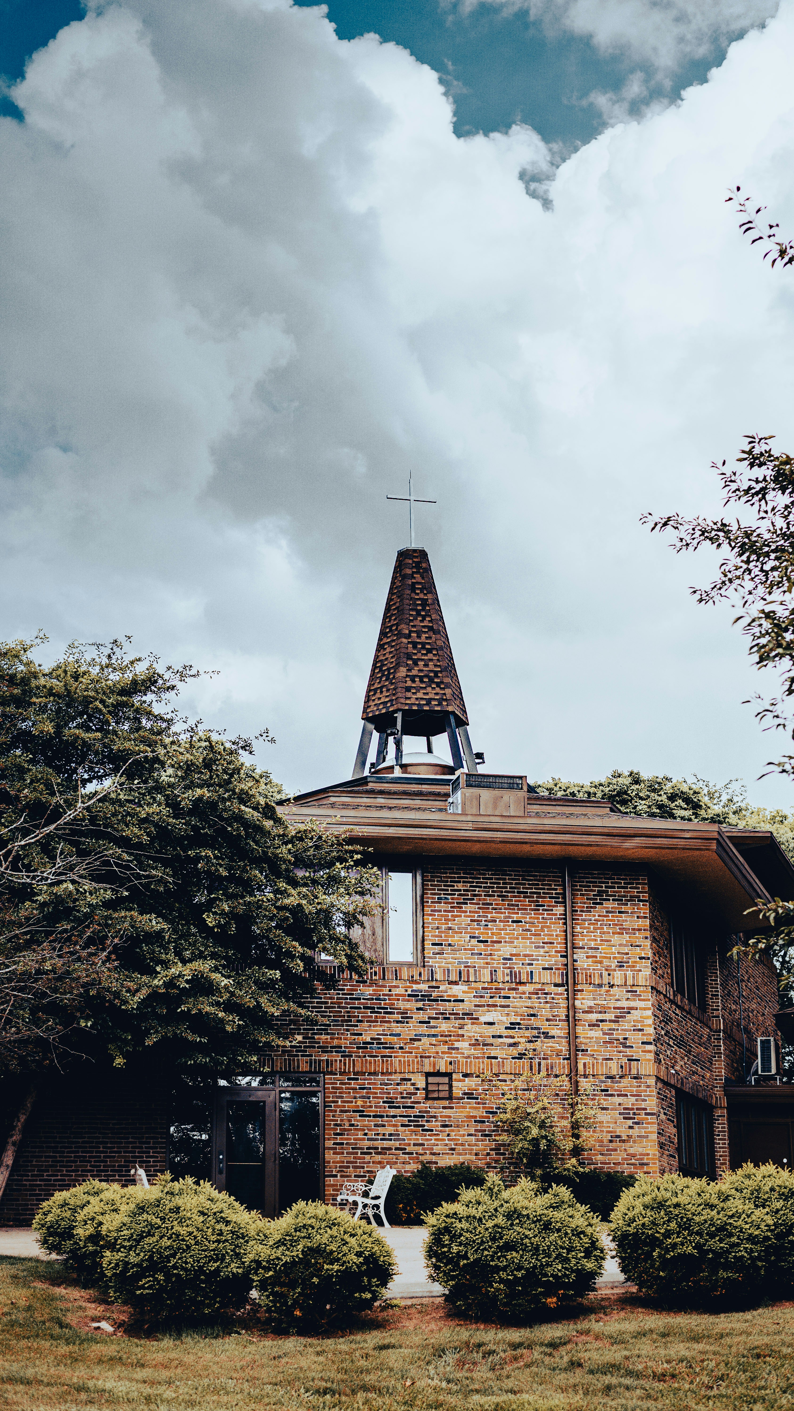 Copper-Topped Spire Over a Brick Chapel Beneath a Sky of Billowing Clouds