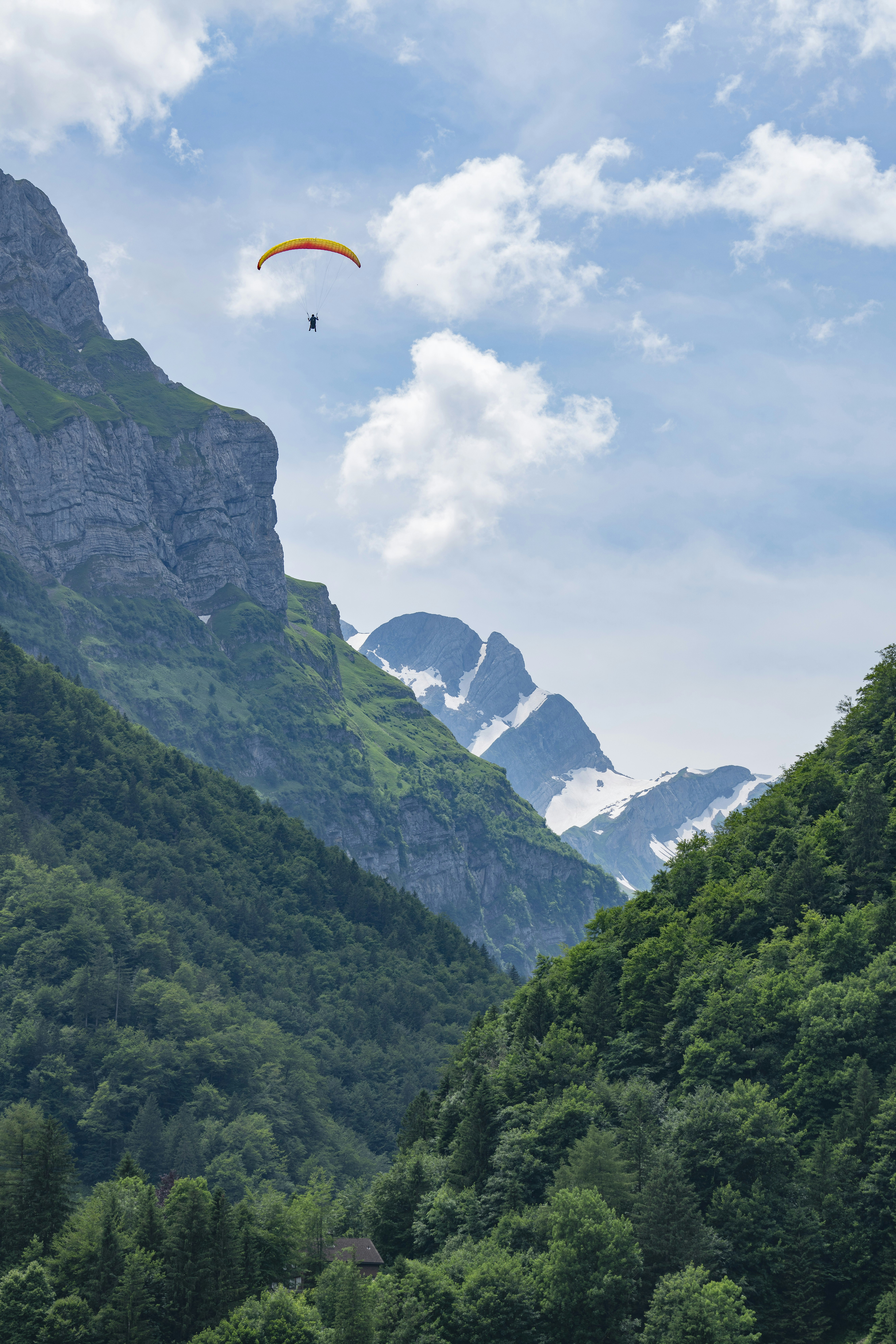 Orange Paraglider Tracing a Corridor Through Alpine Cliffs