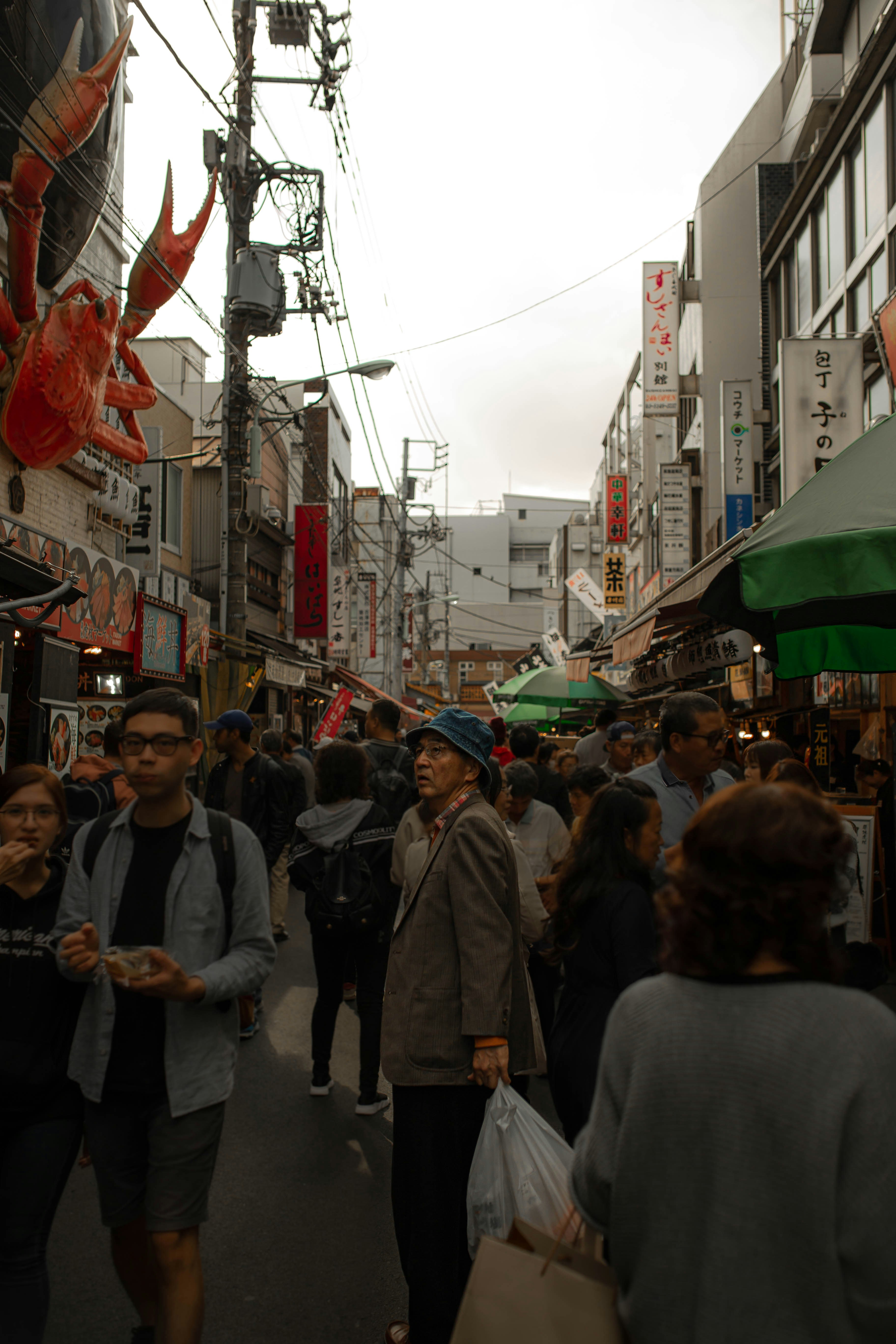 Bustling street market filled with diverse people and vibrant storefronts, showcasing local culture and cuisine.