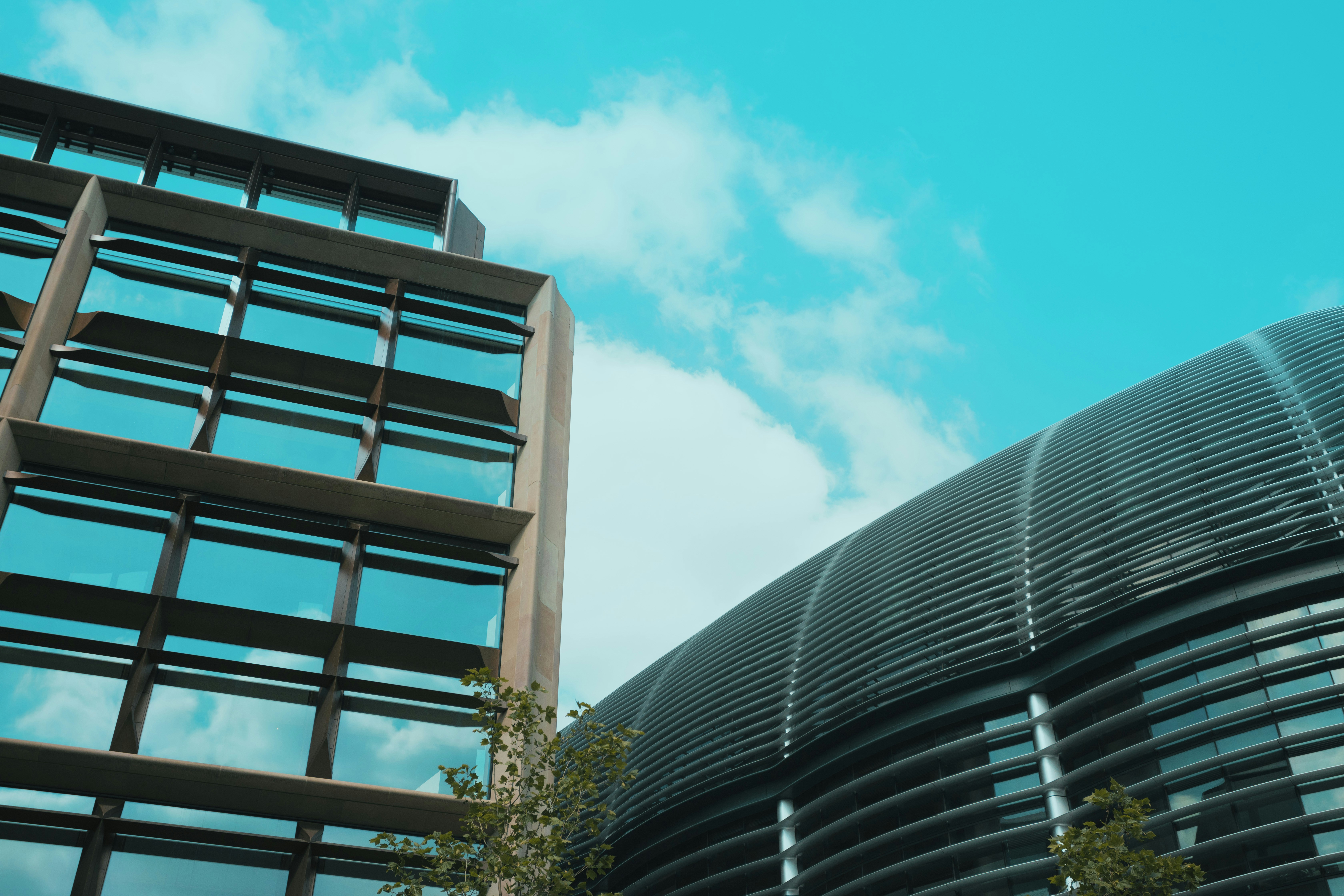 Modern architectural structures with reflective glass and curved metal facades against a bright blue sky.