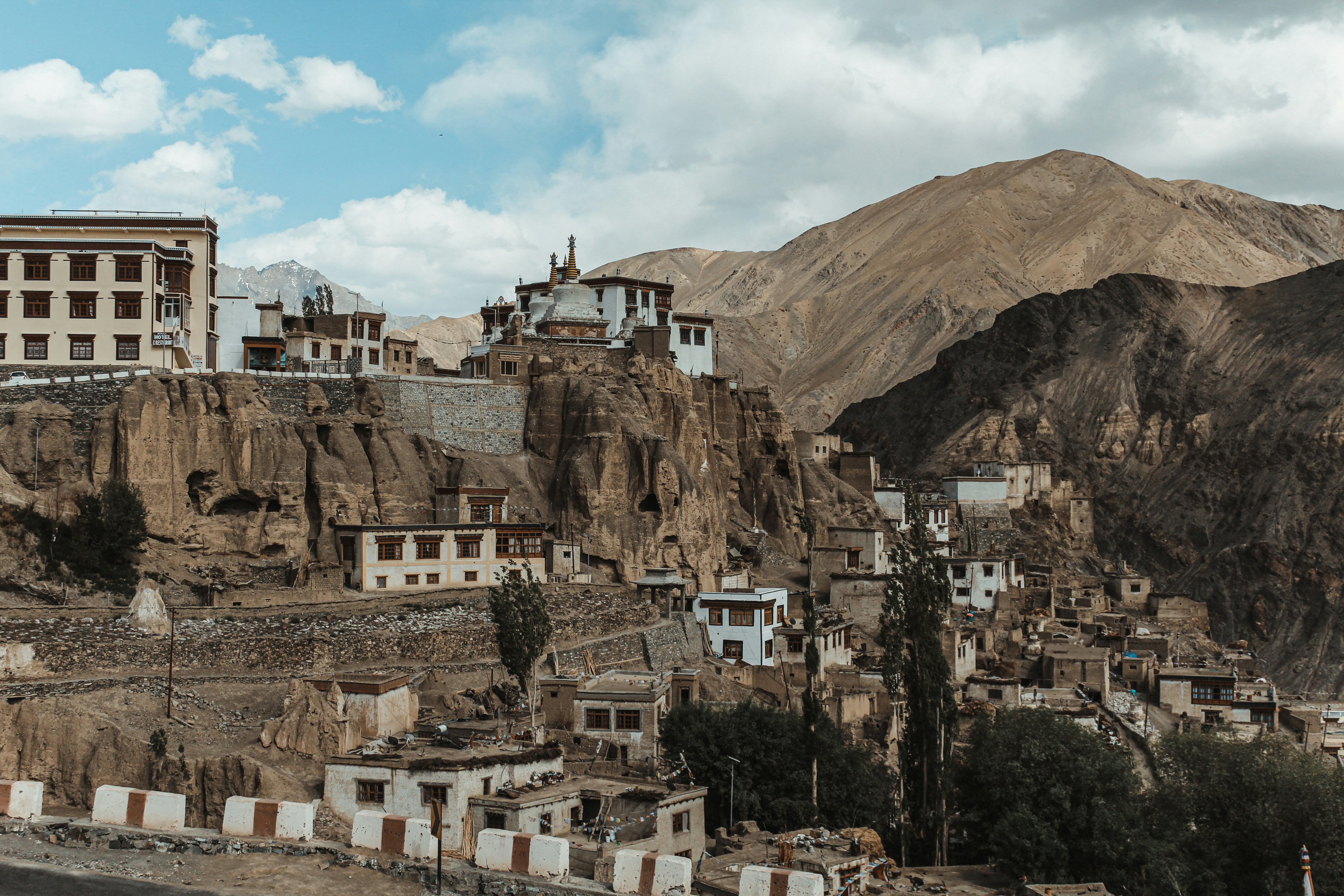Rustic village buildings perched on a rocky hillside under a cloudy sky.