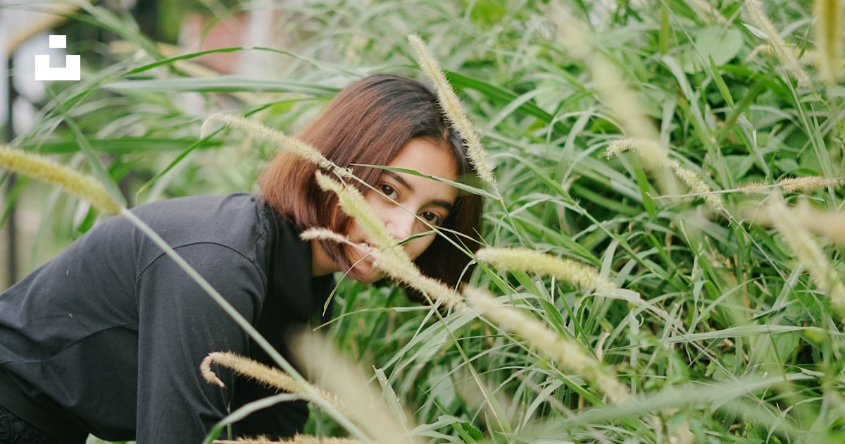 昼間、緑の芝生の上に立つ黒い長袖シャツと黒いズボンを着た女性の写真 Unsplashのファッションの無料画像