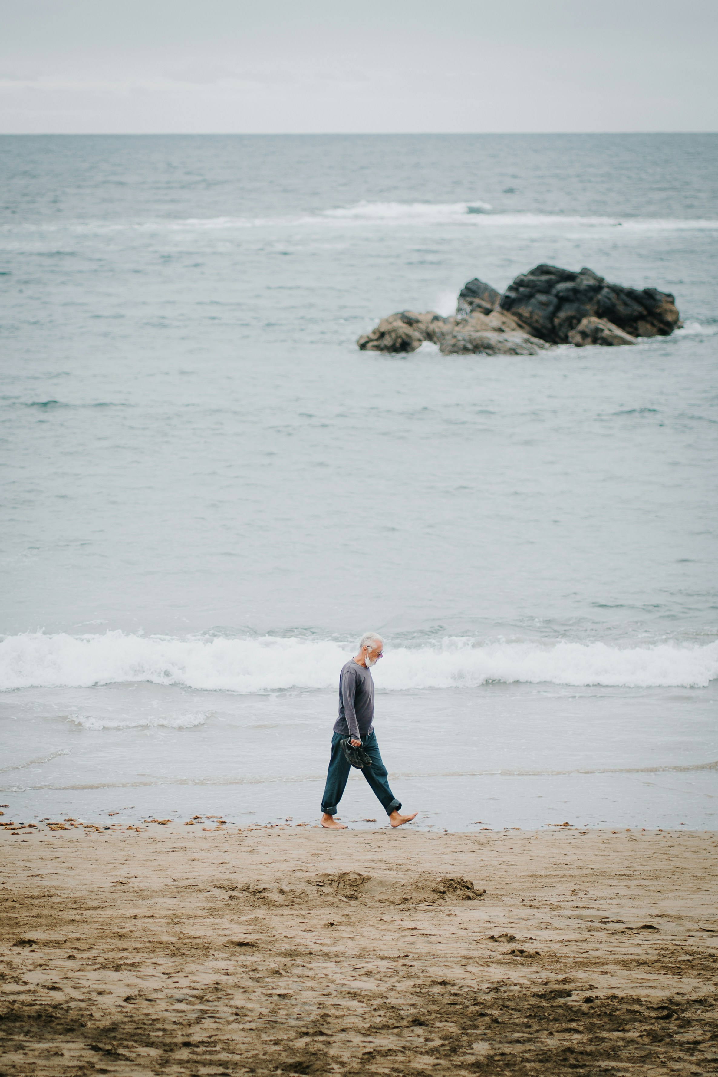 woman in black and white dress walking on beach during daytime