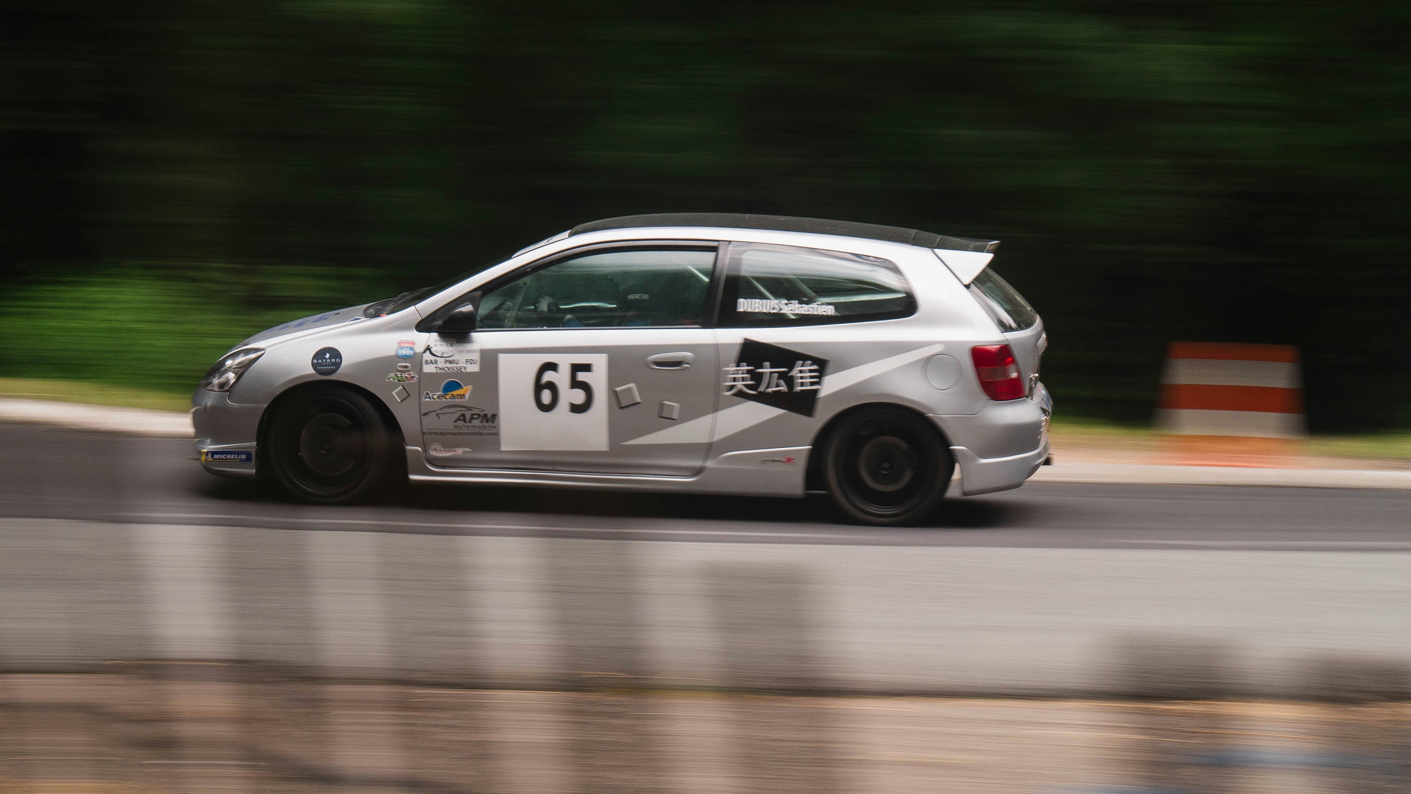 Number 65 Cutting Through the Curve: A silver race hatchback in motion