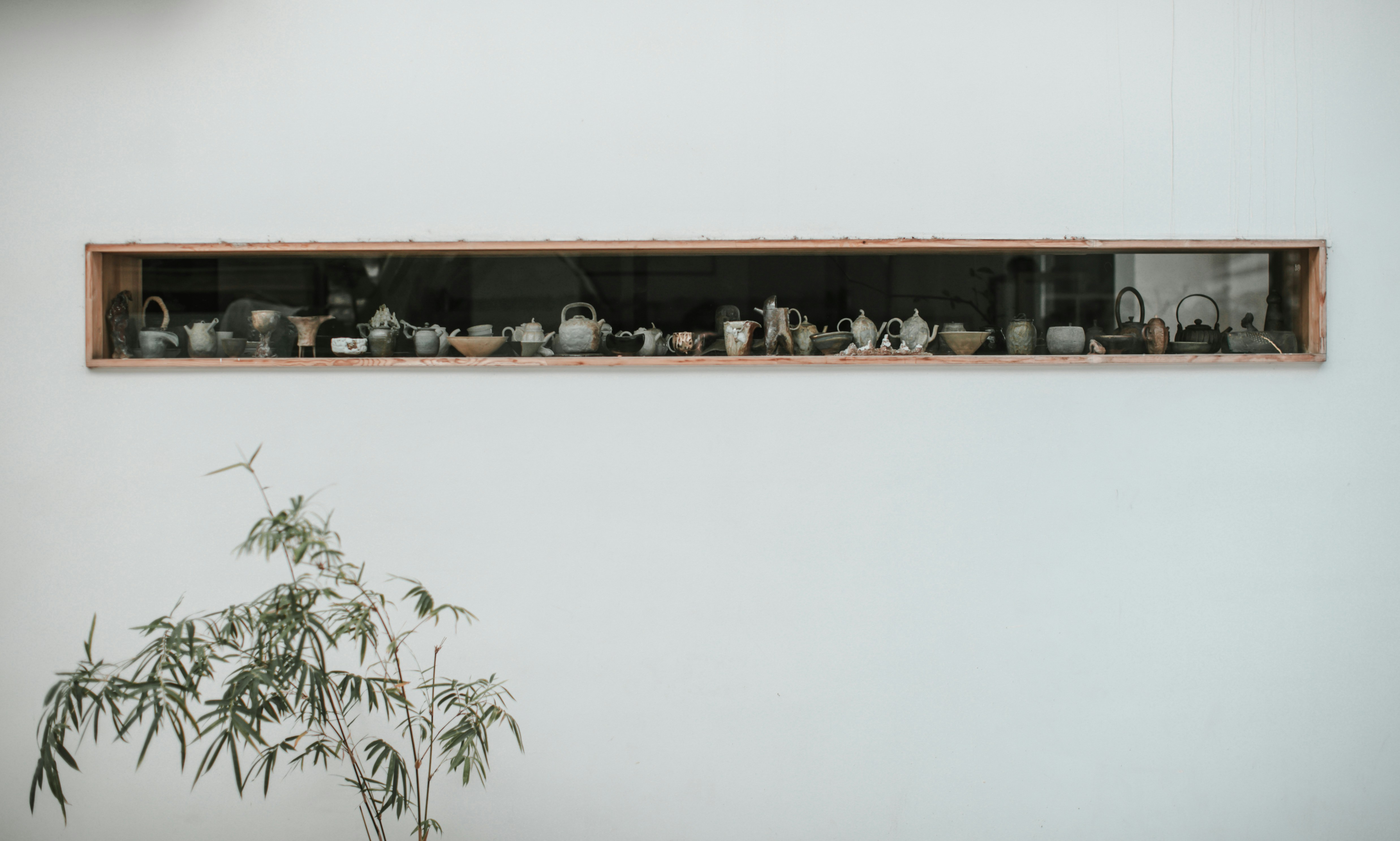 Ceramic Echoes: Teapots Arranged in a Narrow Window