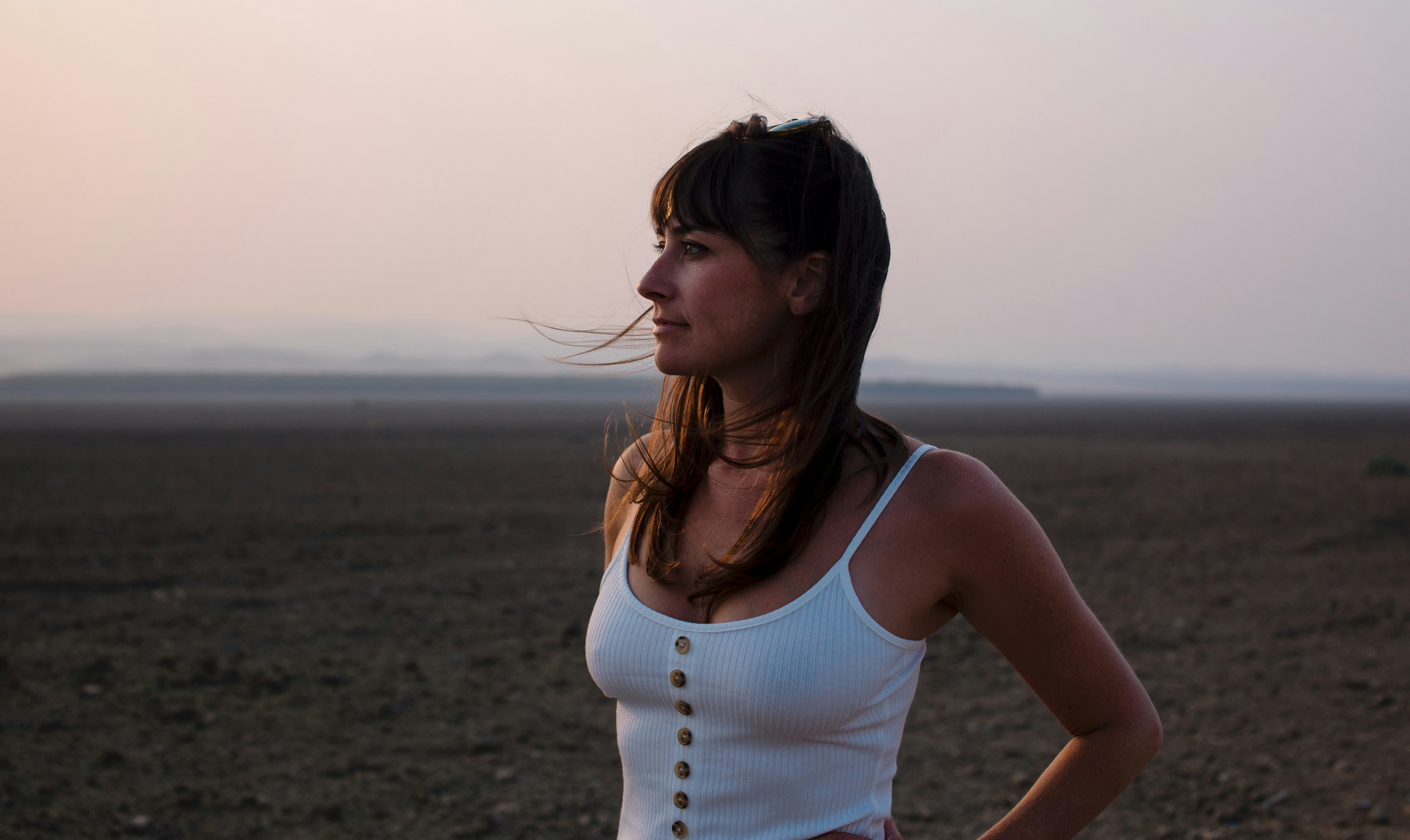 A woman looks out at a dry field during California wildfire season. 