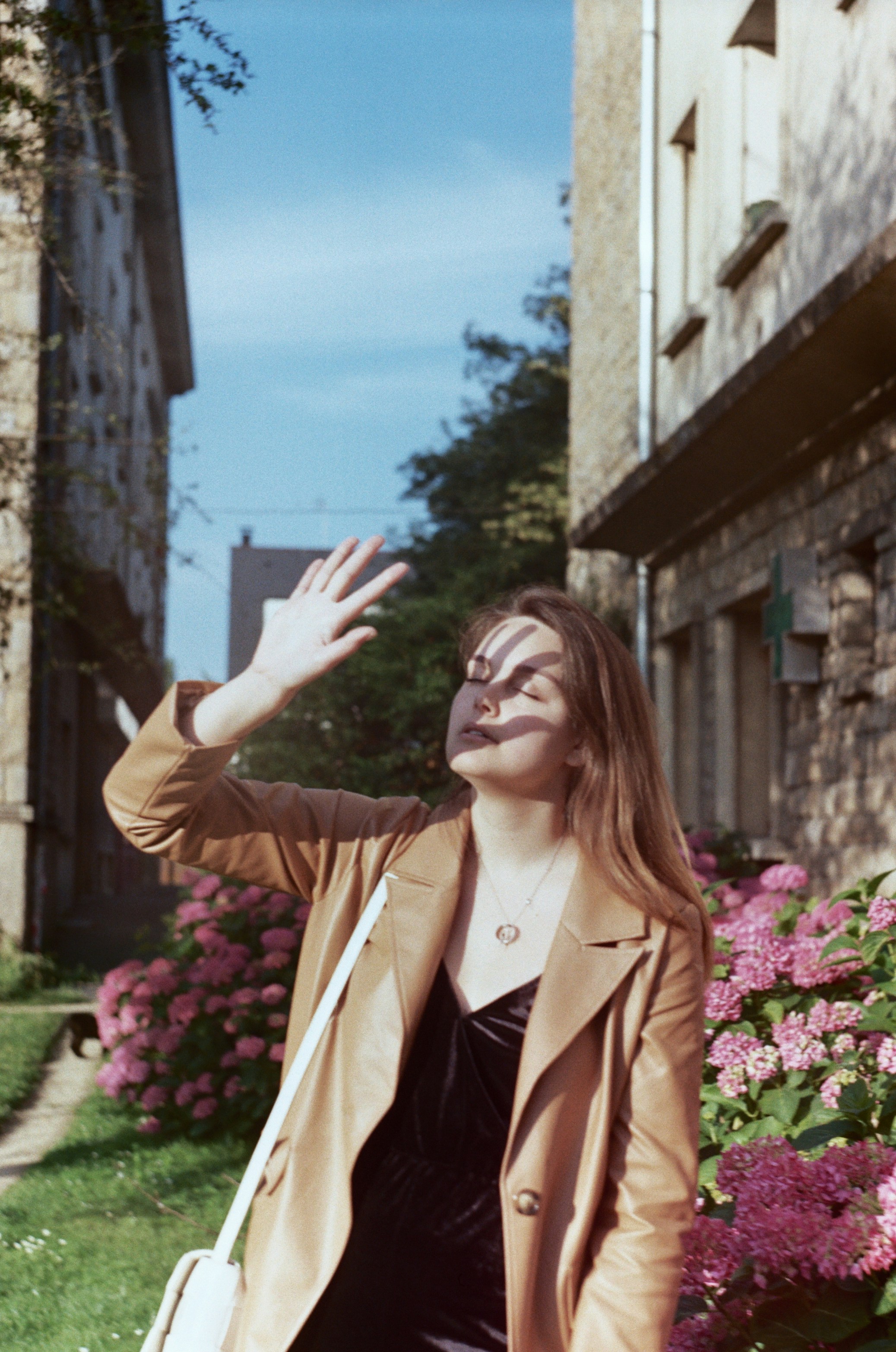 Sunlit silhouette: a woman shields her face amid a town garden bloom