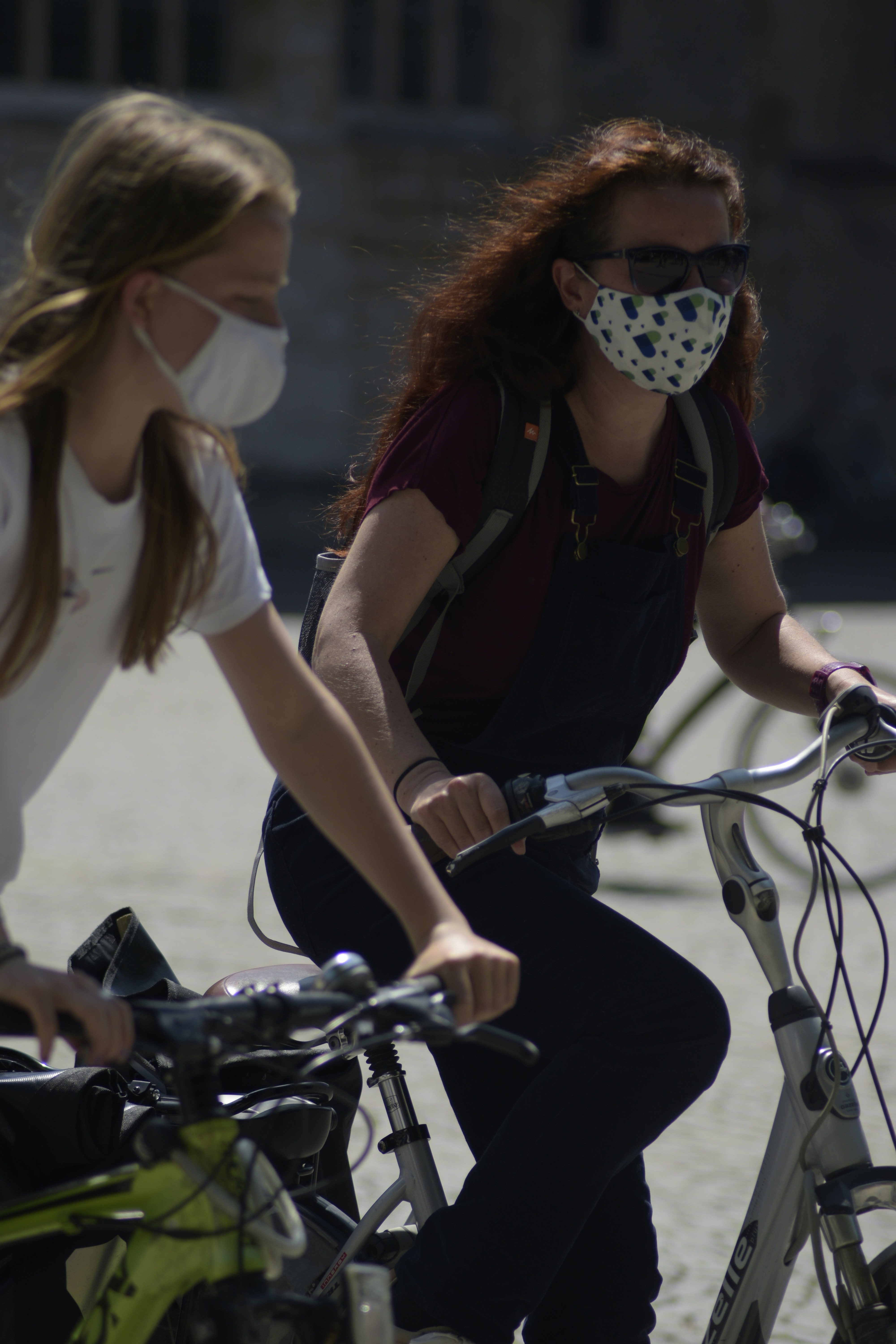 Sunlit City Ride: Masked Cyclists in Motion