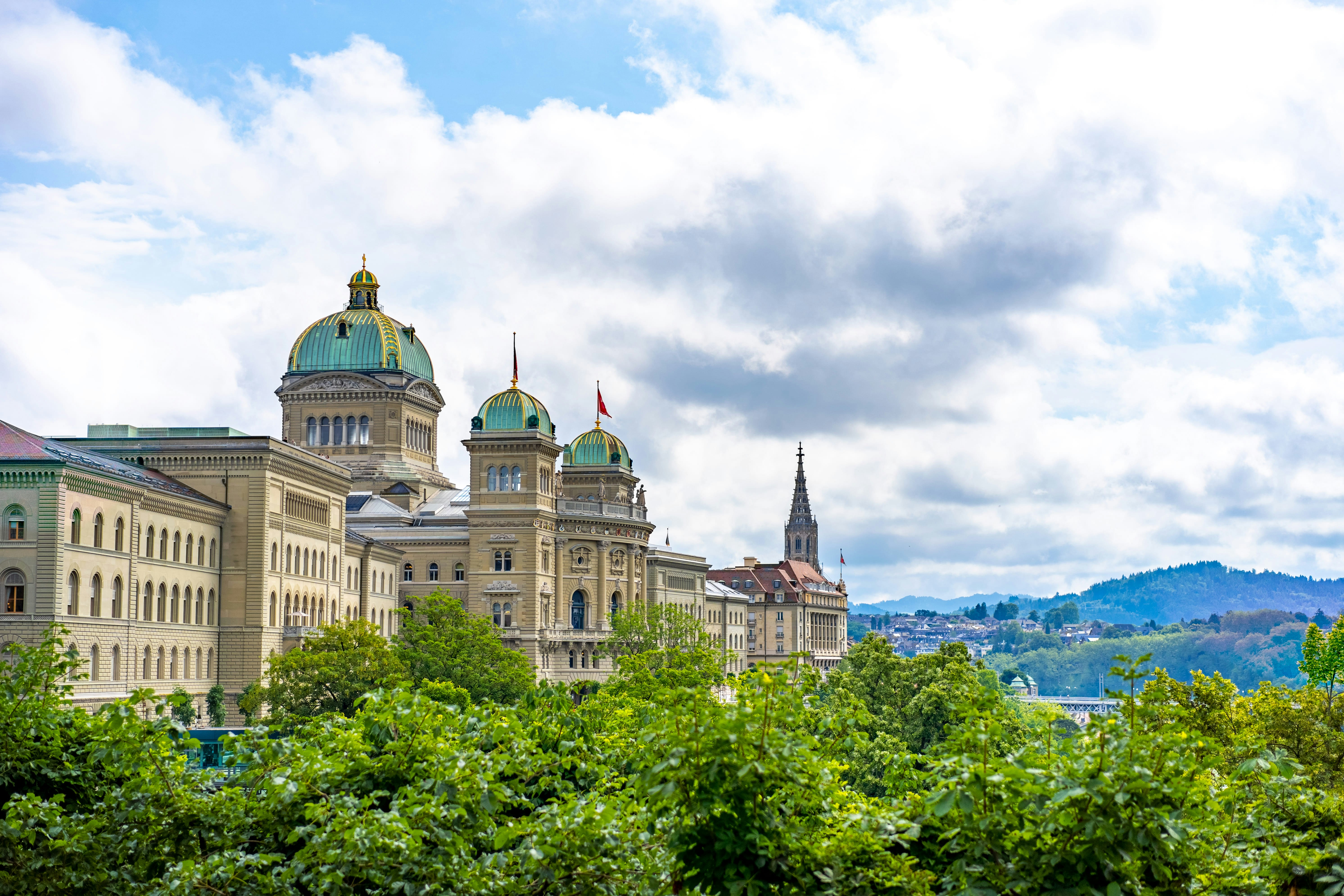 White and green concrete building near green trees under white clouds ...
