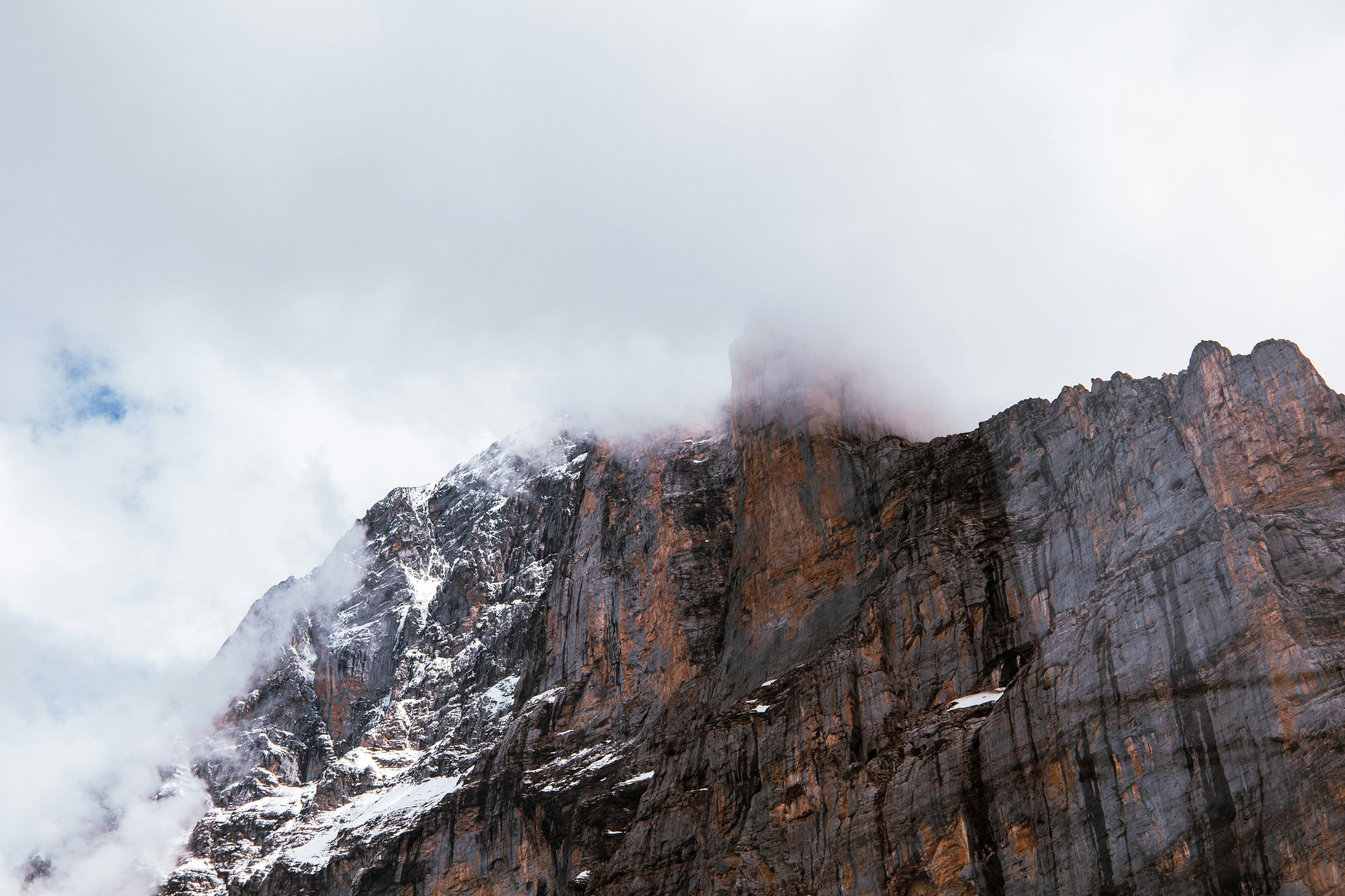 Snow-capped mountain peaks partially obscured by swirling clouds, showcasing the rugged beauty of the landscape.