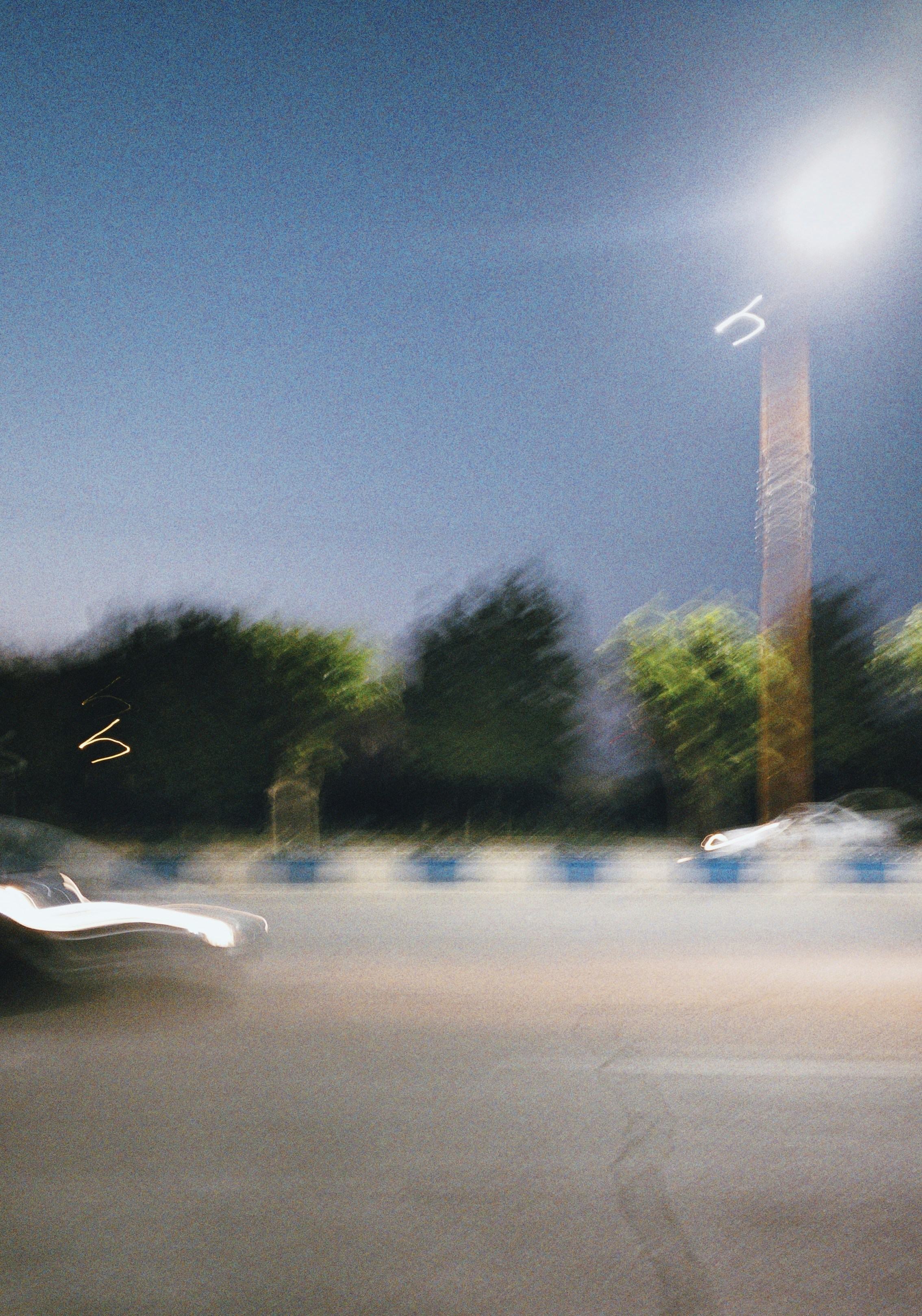 Blurred Motion under a Neon Night: A Streetlight Glow and Passing Cars