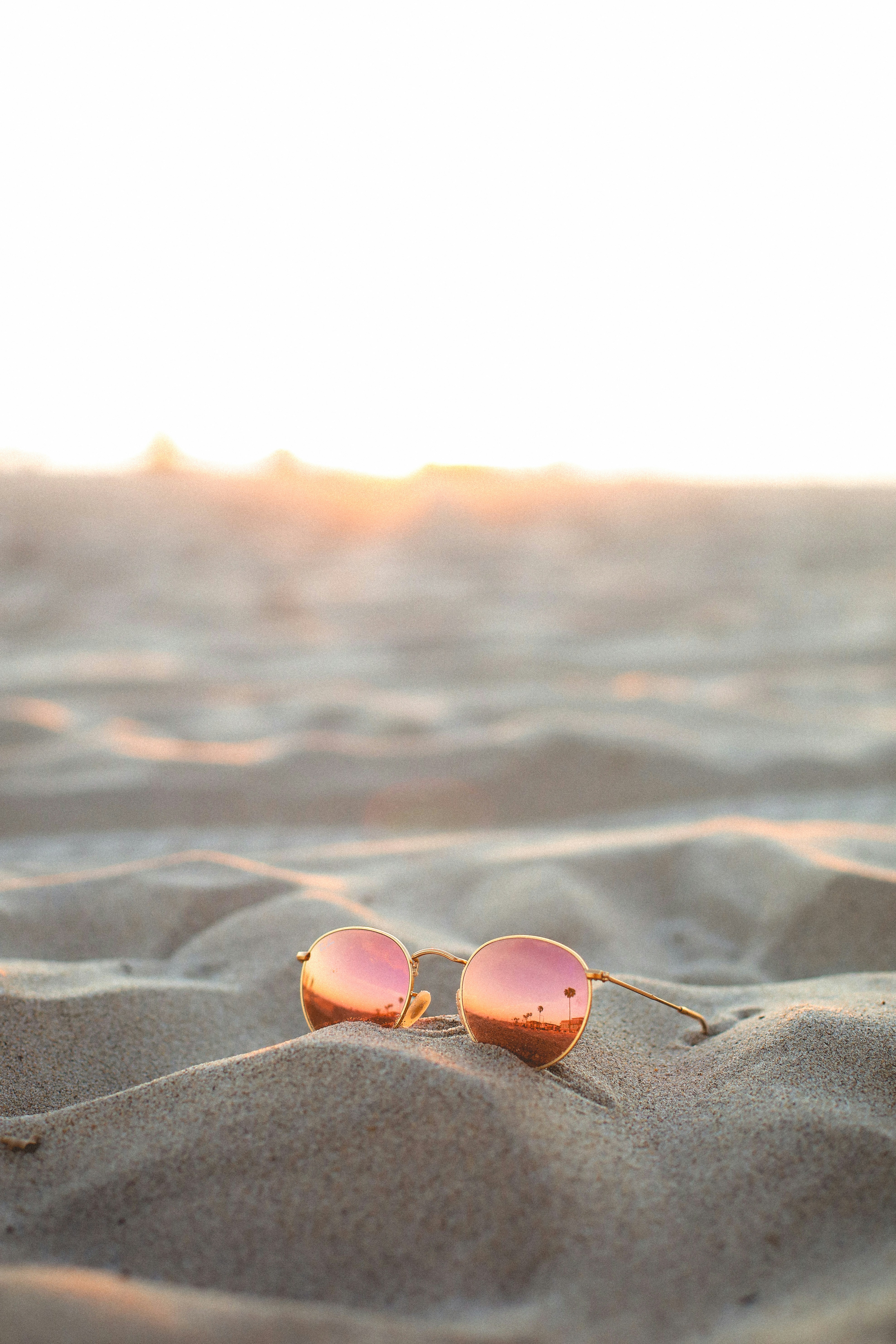 Rose-Gold Glasses Resting on Quiet Sand at Sunset