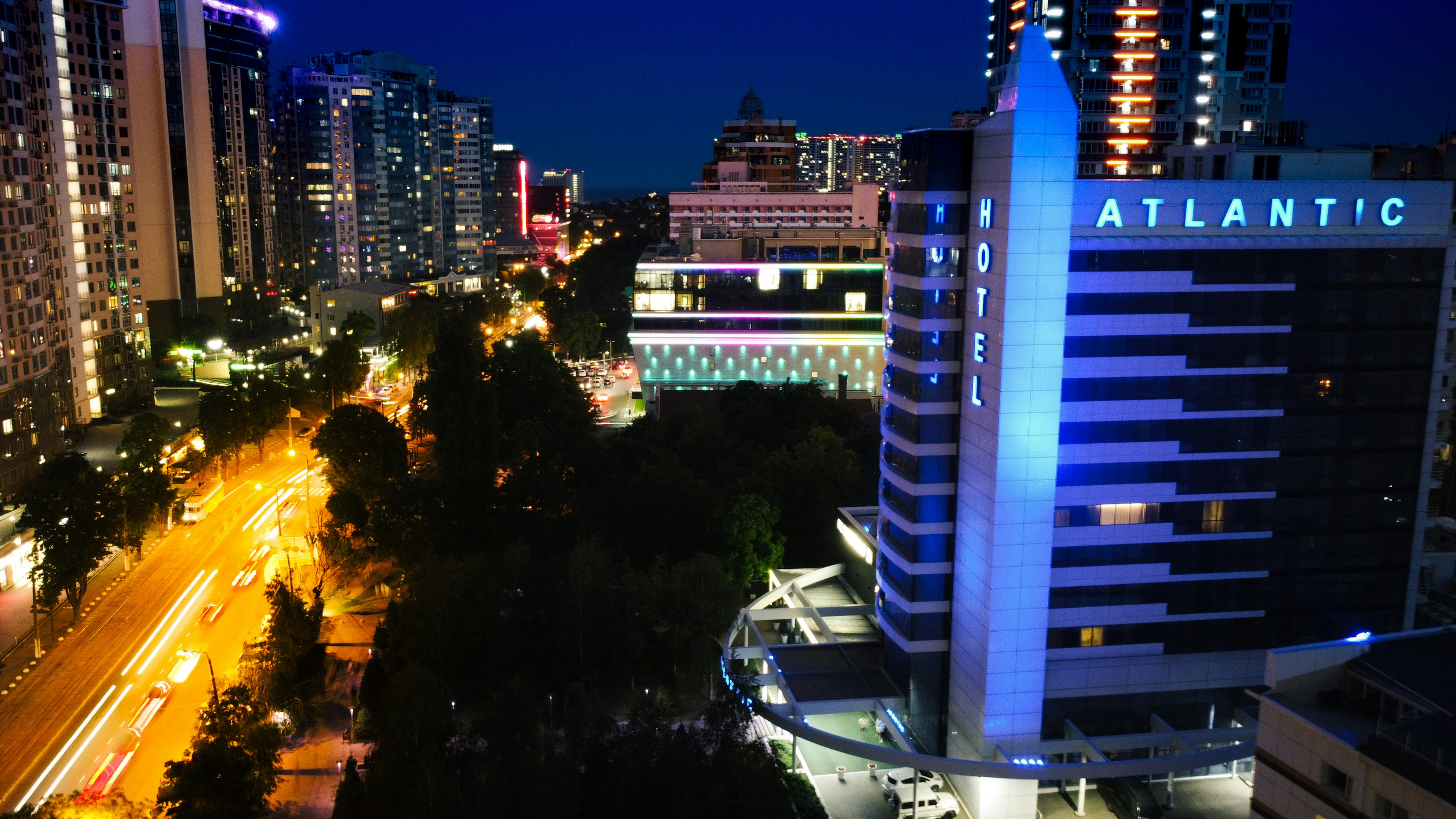 Illuminated Atlantic Hotel stands prominently against a backdrop of vibrant city lights at night.