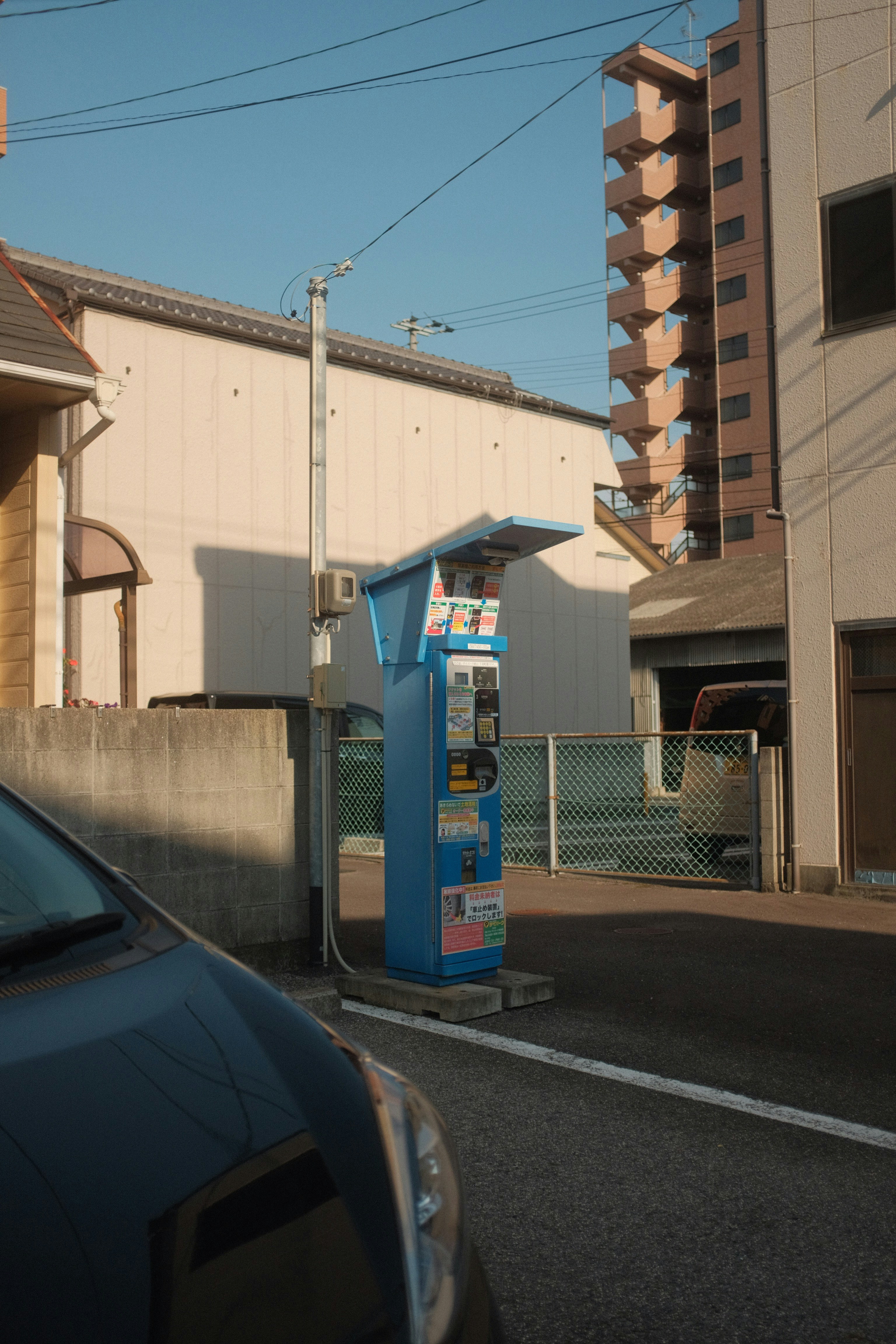 blue and white trash bin beside white metal fence