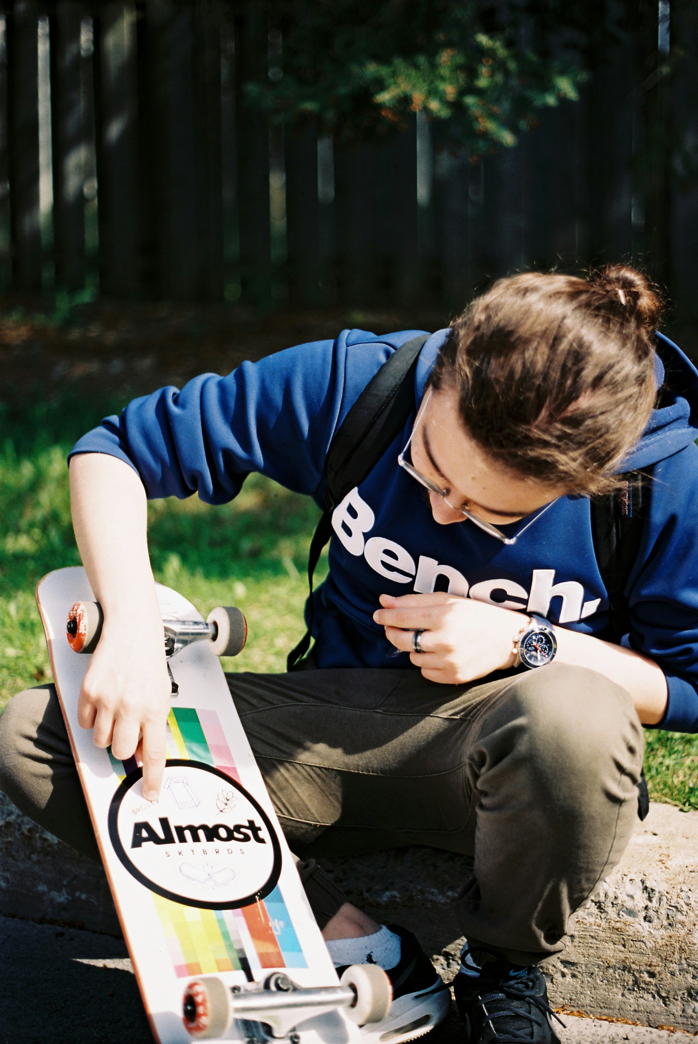 Skateboard enthusiast customizing deck with colorful graphics while seated outdoors.