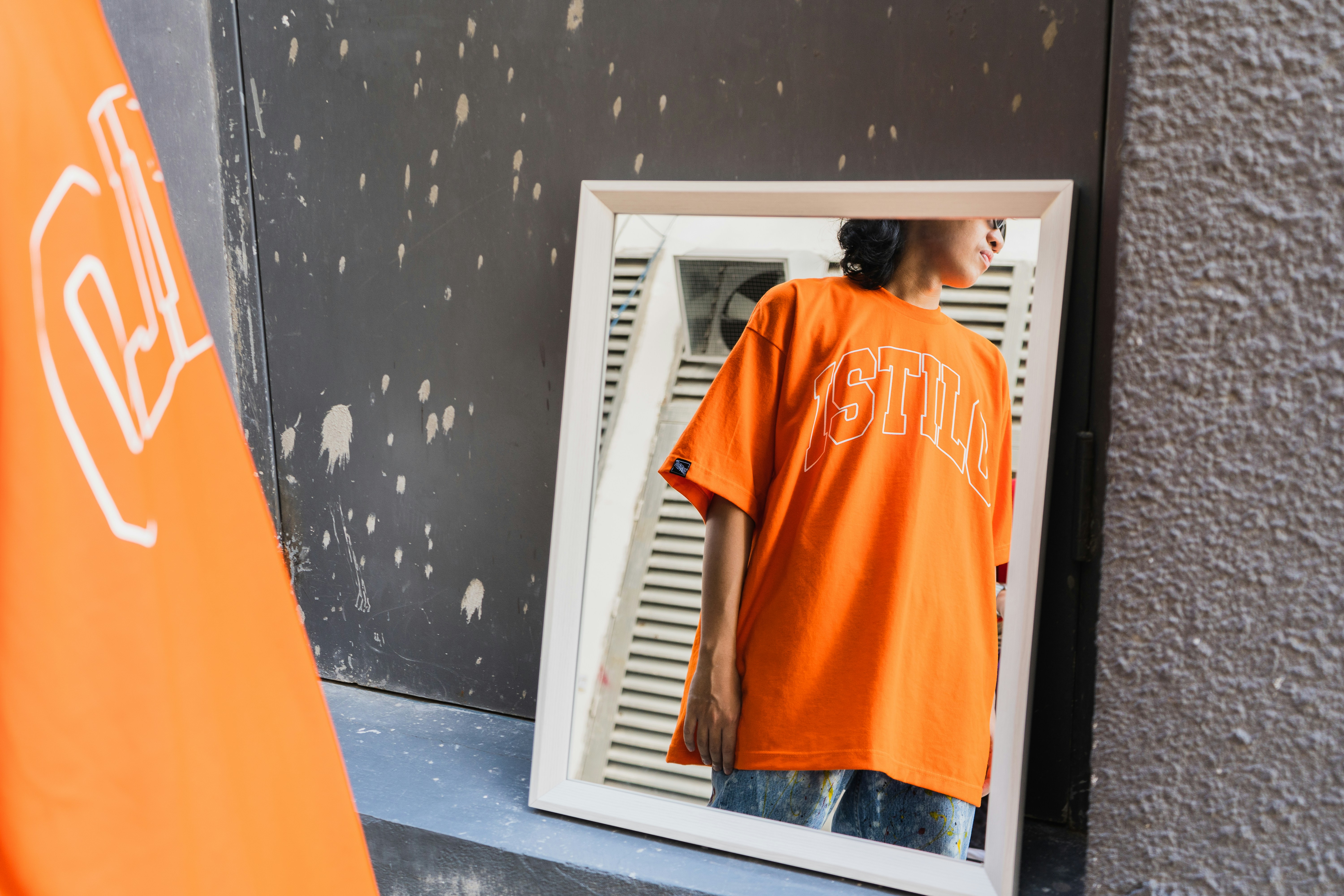 Orange Tee Reflected in a Leaning Mirror: Textures and Quiet Geometry