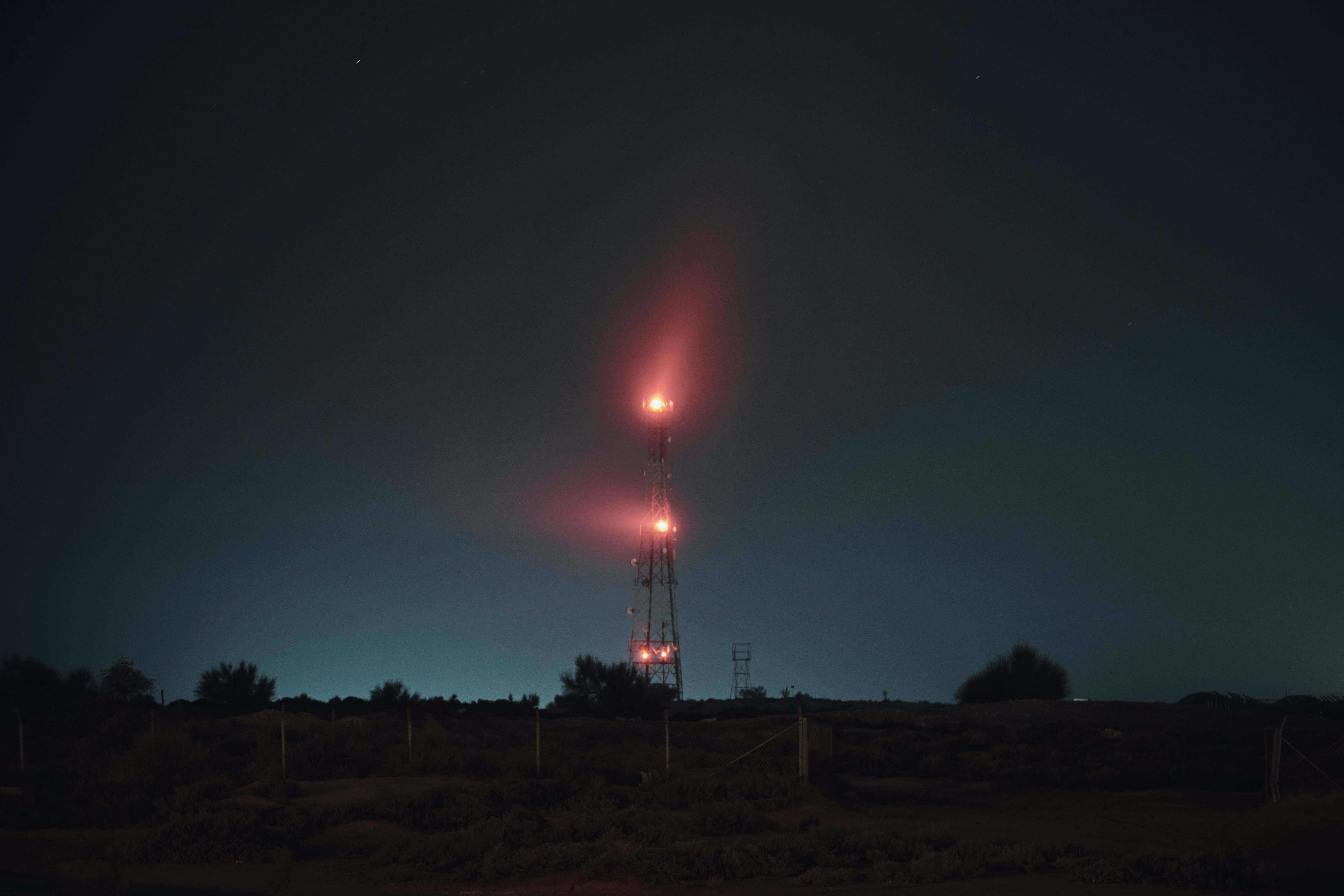 a radio tower in the middle of a field at night