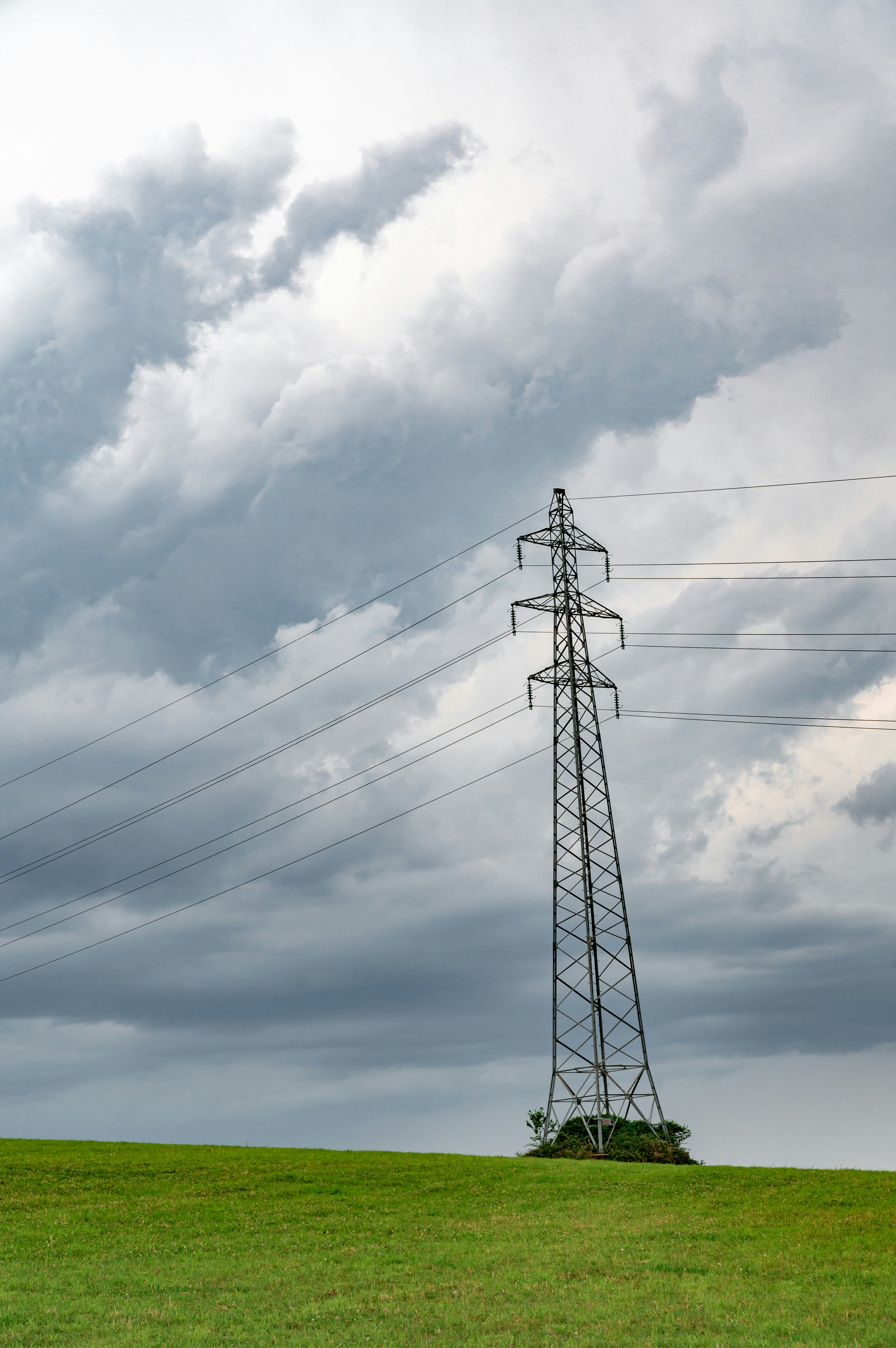 Lone Pylon on a Green Hill Beneath Turbulent Skies