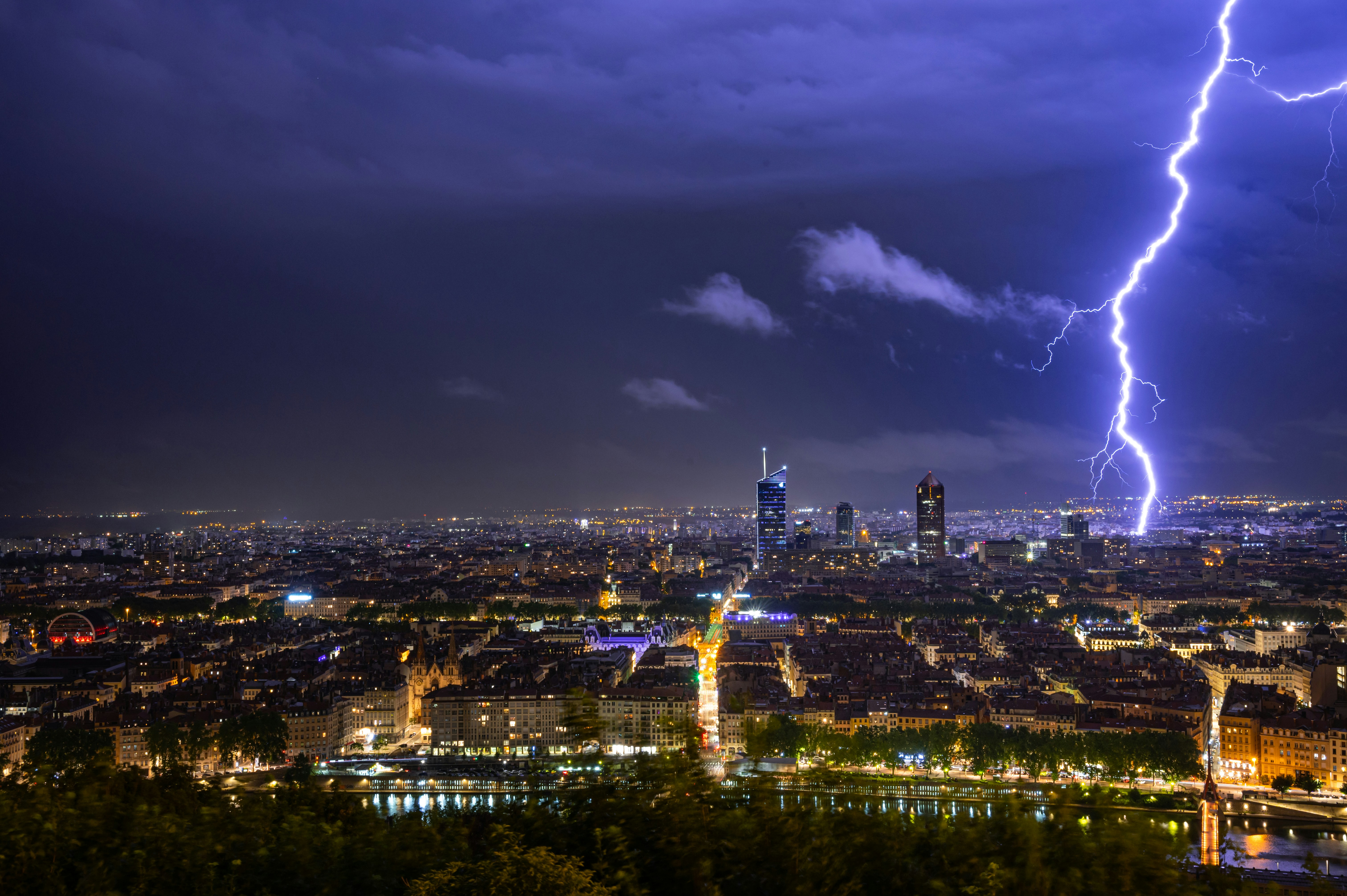 Lightning bolt striking above a city skyline under a dramatic night sky.