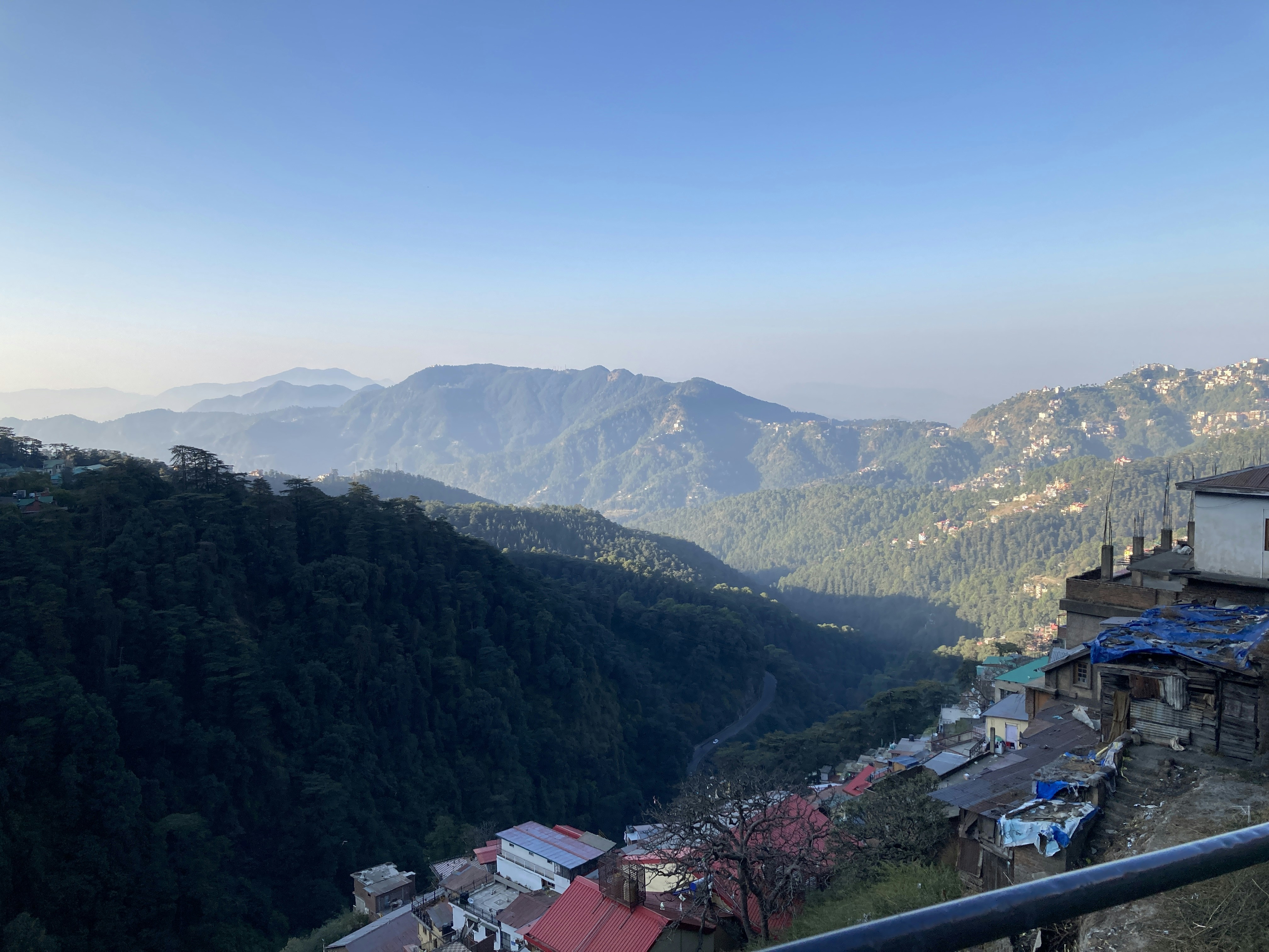 Expansive view of layered mountains and valleys, showcasing the beauty of nature and the tranquility of a hillside village.