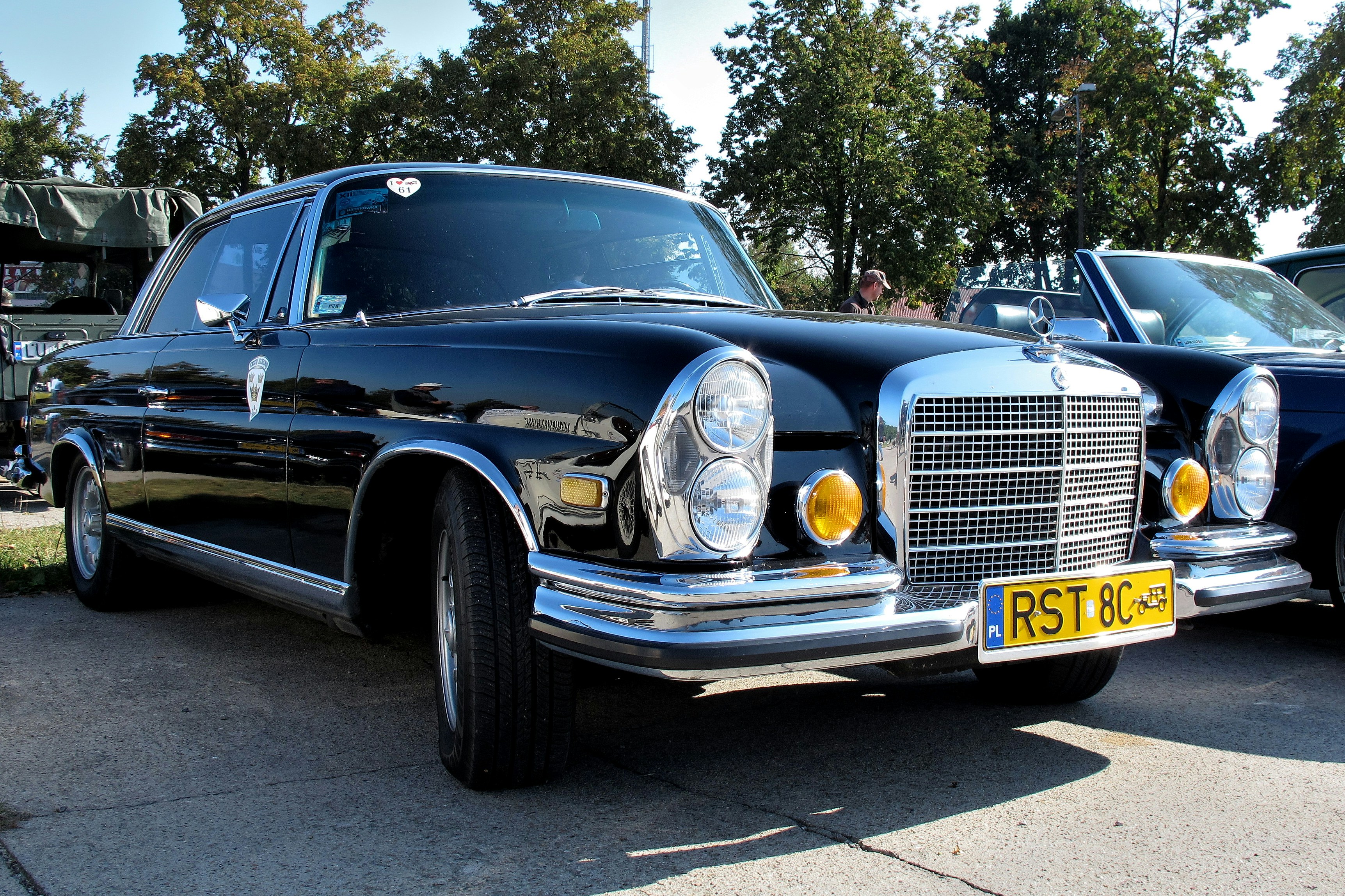 Classic black Mercedes-Benz parked under a clear blue sky, showcasing its vintage design and chrome detailing.
