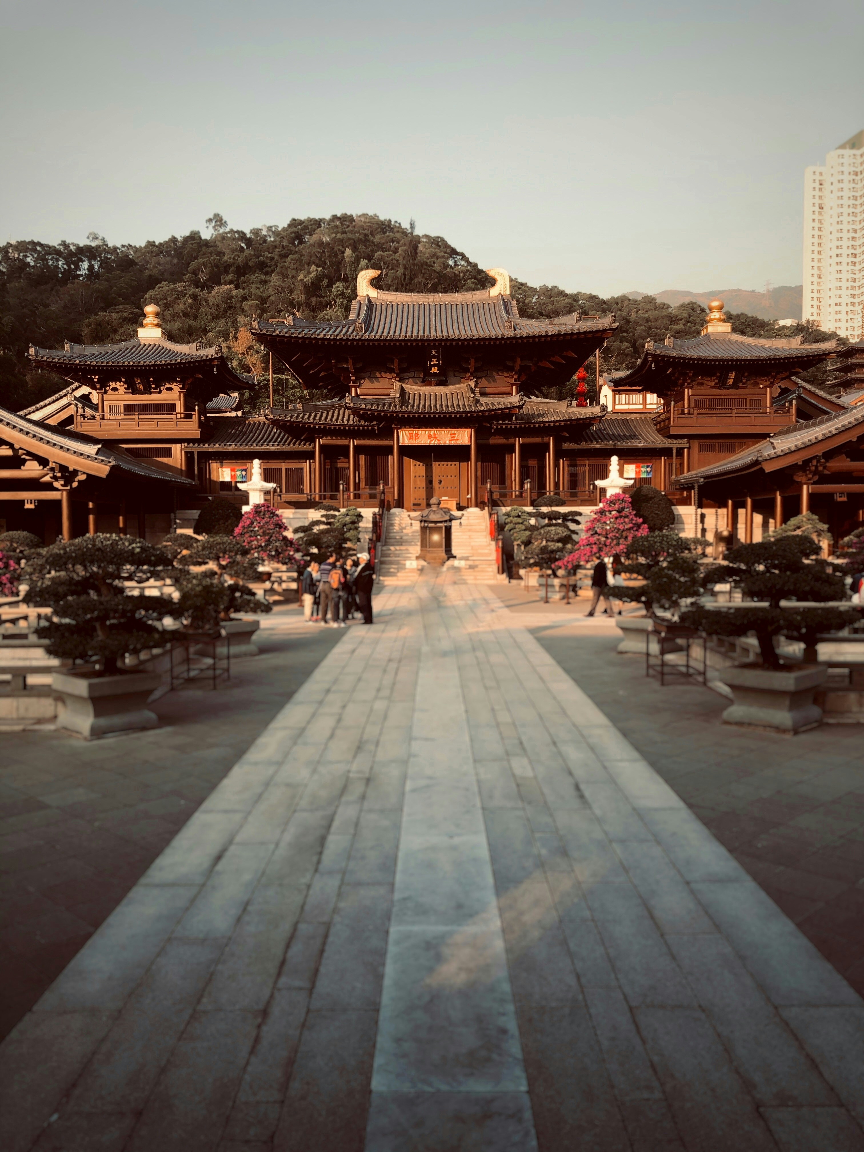 Traditional temple complex with intricate wooden architecture and vibrant floral arrangements, set against a mountainous backdrop.