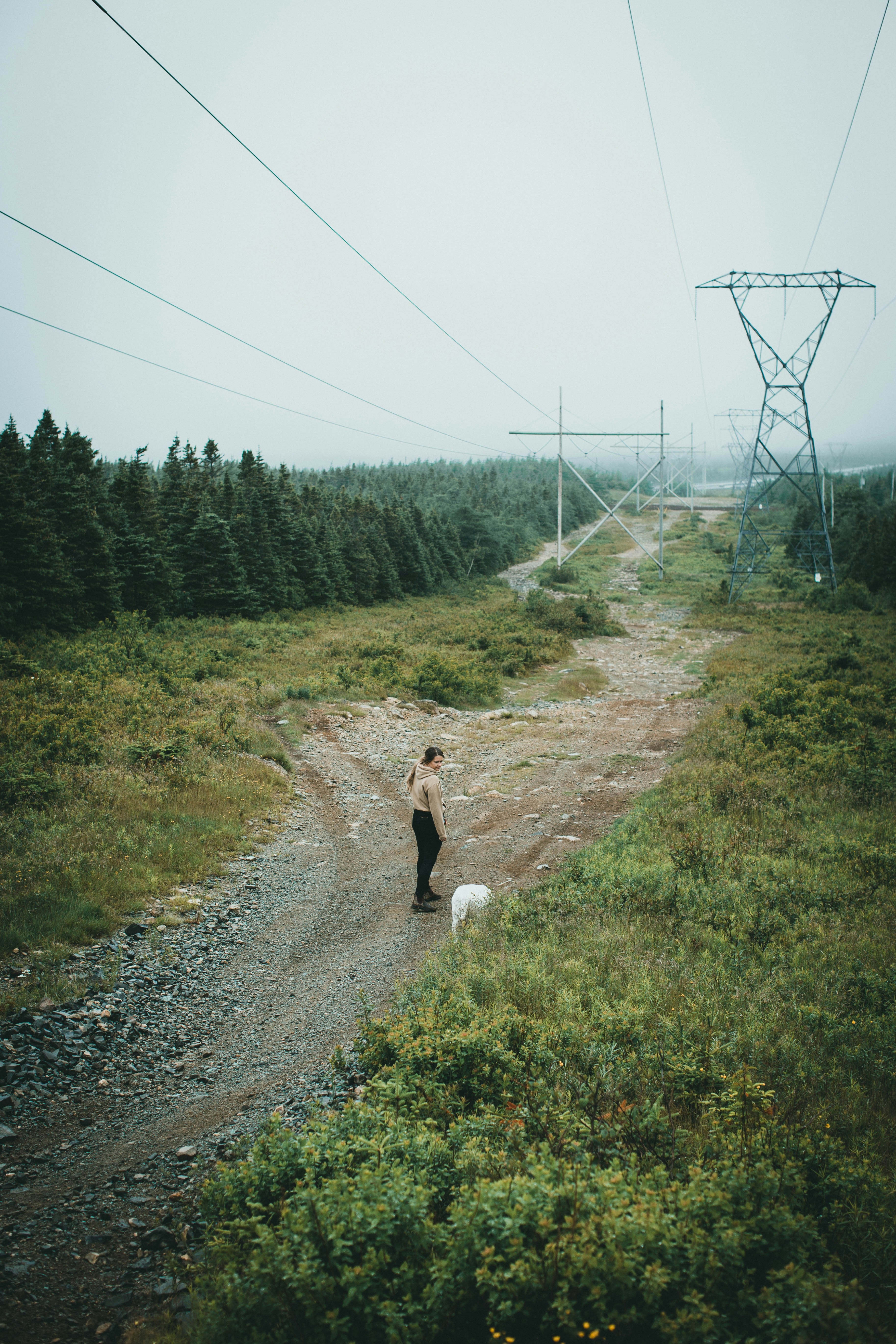 girl in white jacket walking on pathway between green grass field during daytime