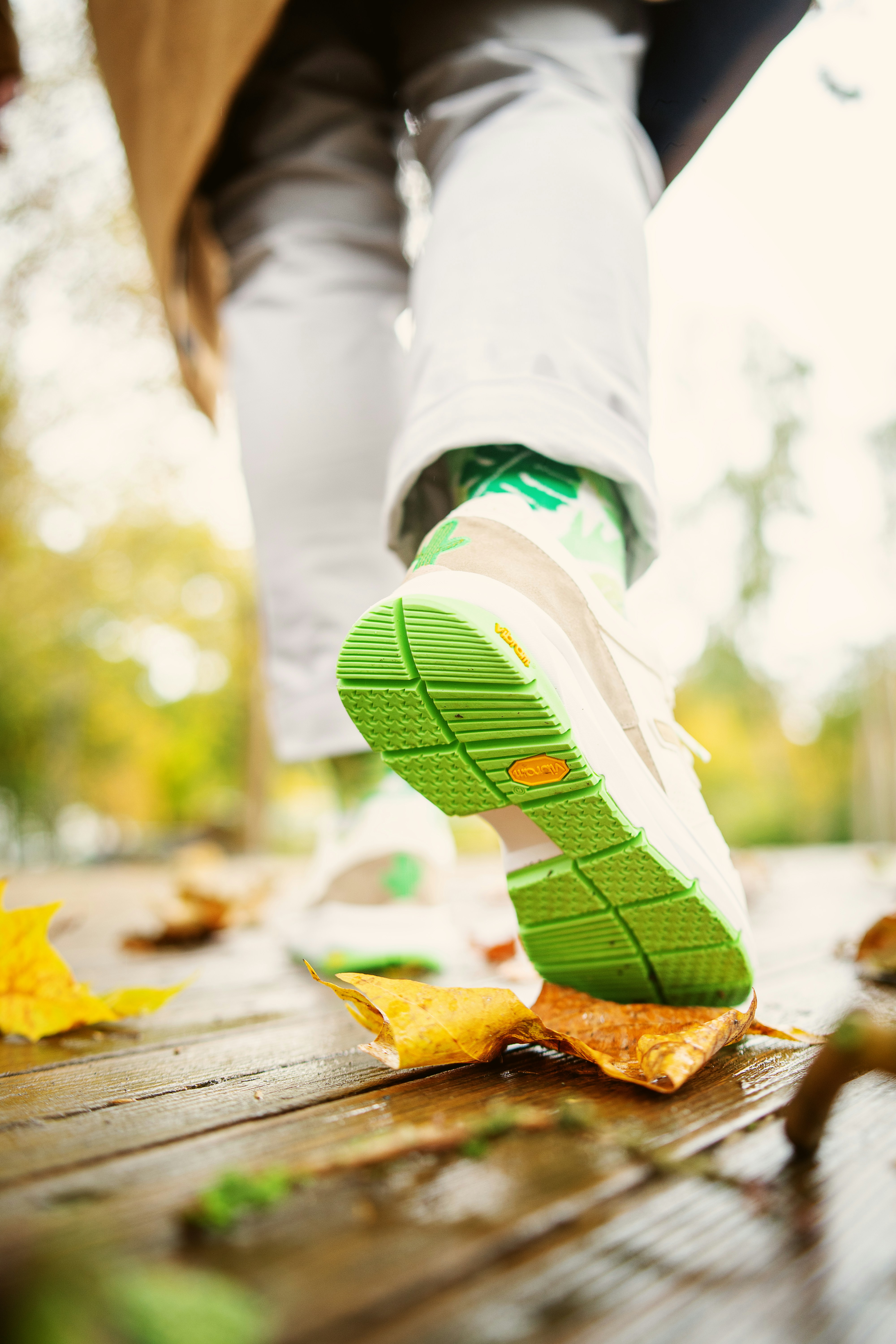 Step Through Autumn: Green-Soled Footstep on a Wet Boardwalk