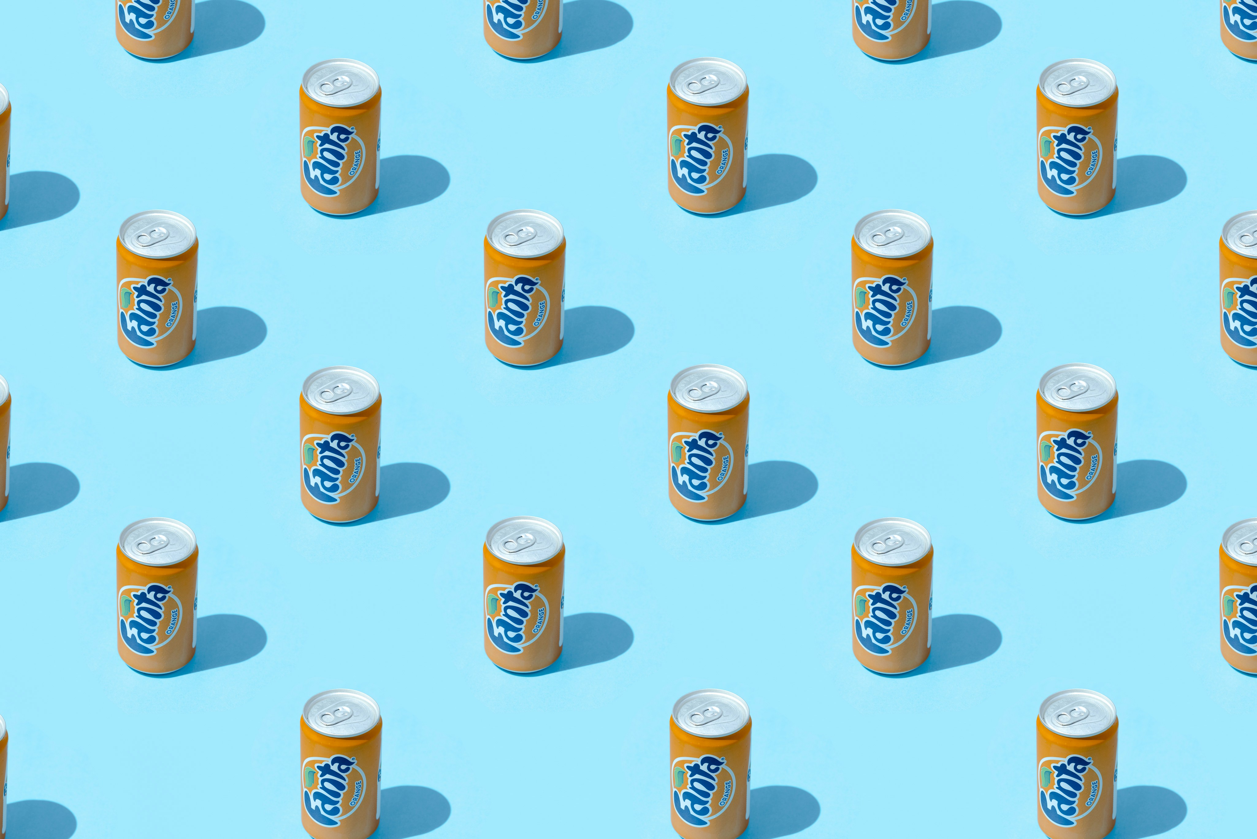 Midfield Pop: a candy-tolk pattern of Fanta cans across a bright blue canvas