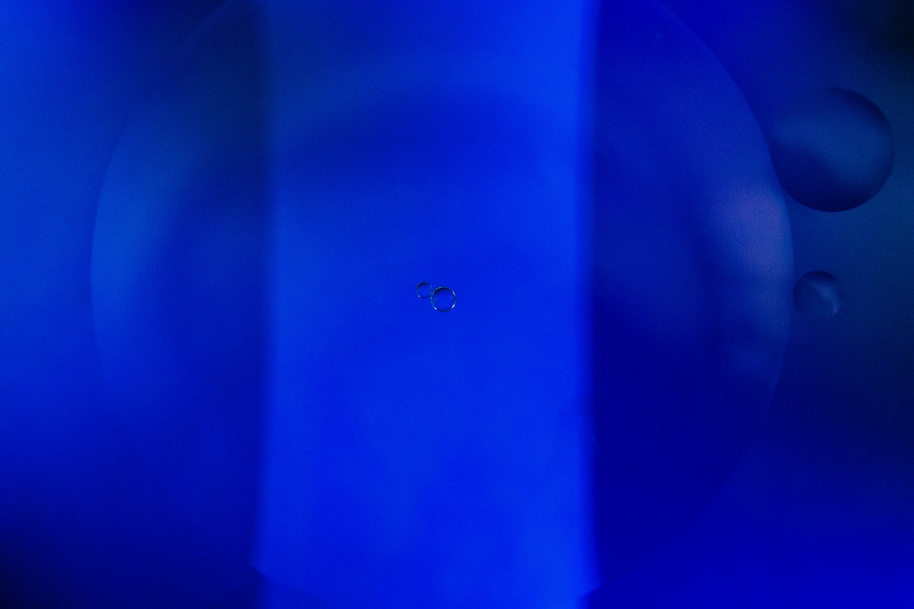 Abstract interplay of oil droplets suspended in a deep blue liquid.