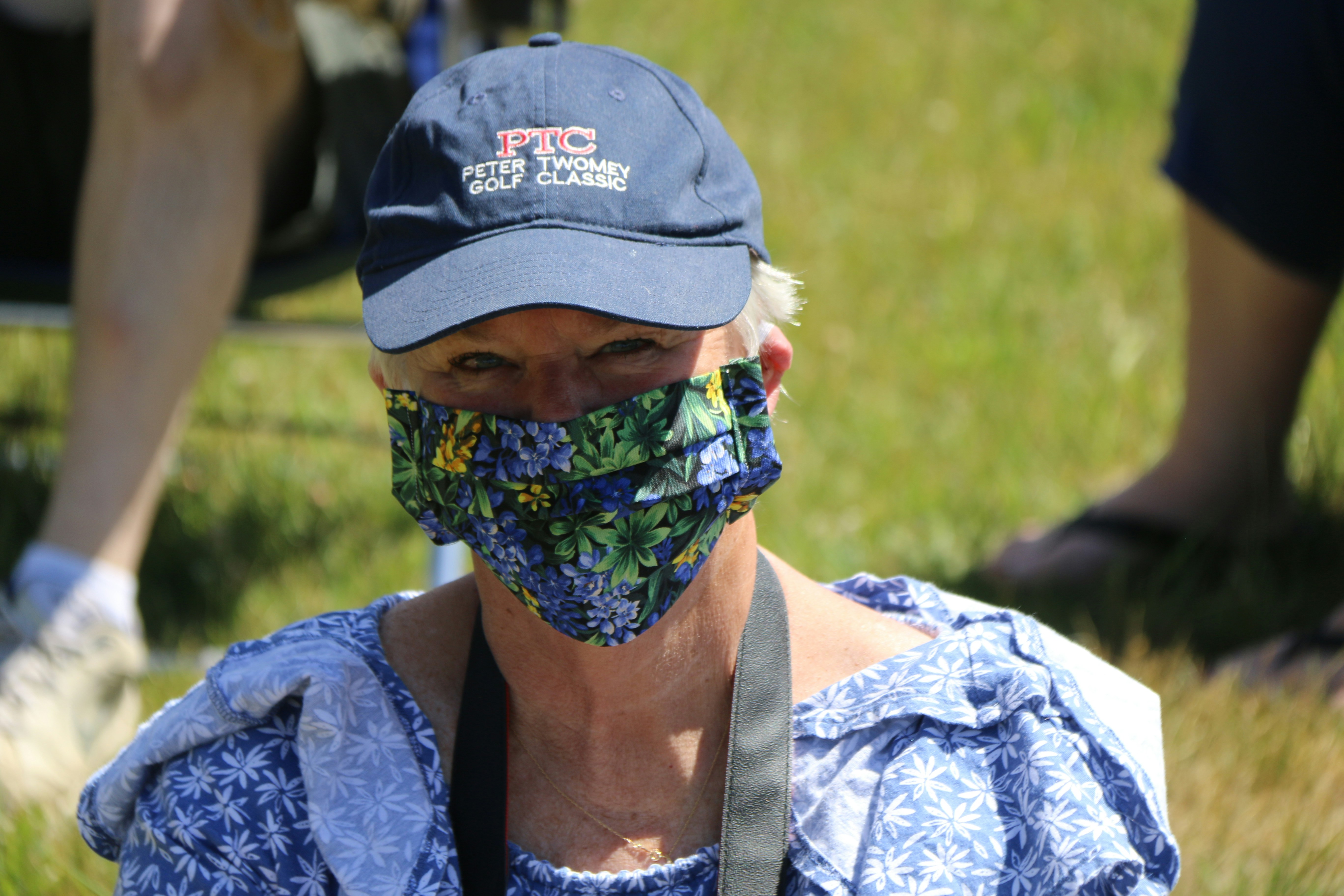 Masked Woman in Floral Attire on a Sunlit Field