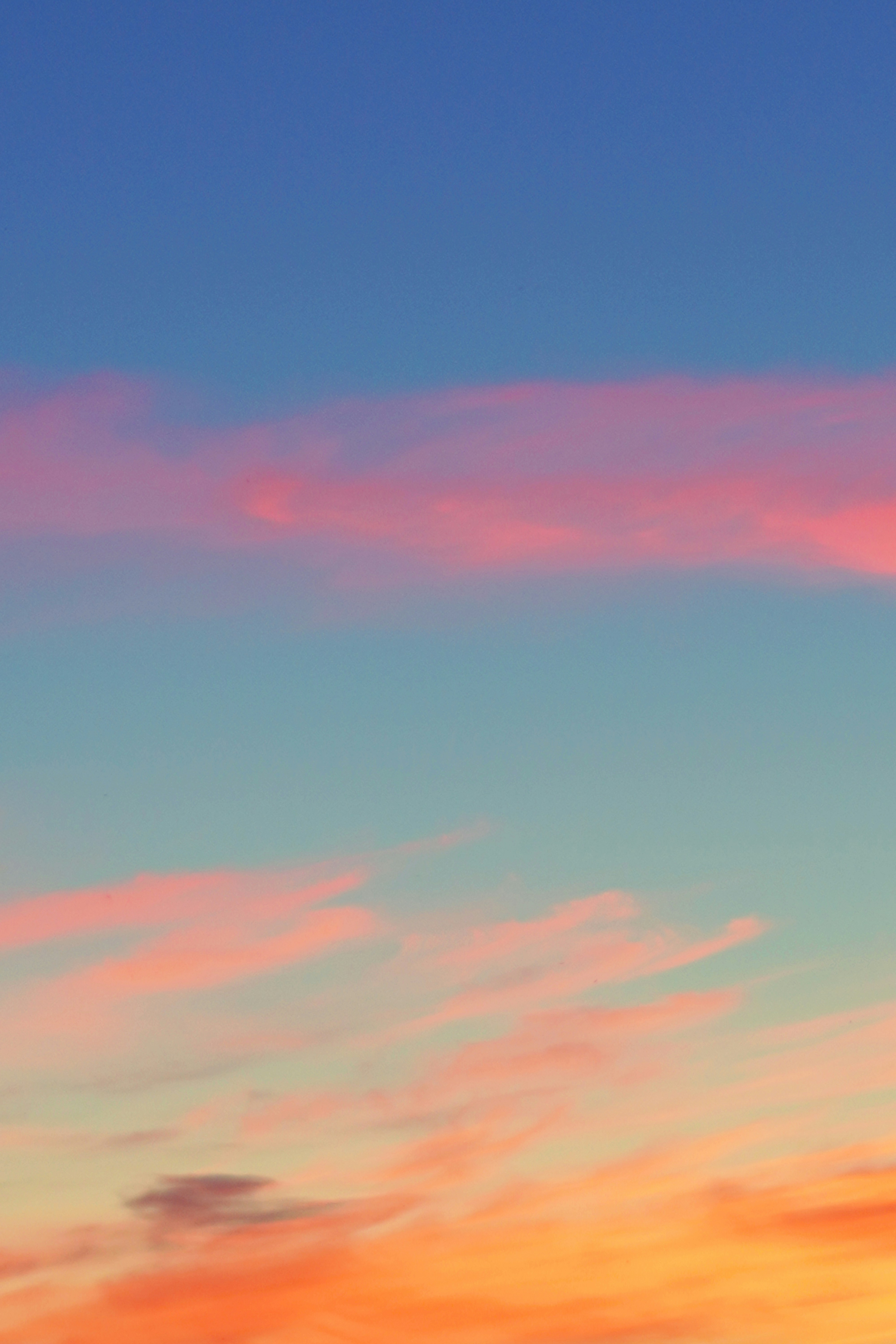 Soft pastel clouds merge in a gradient sky as day transitions to night.