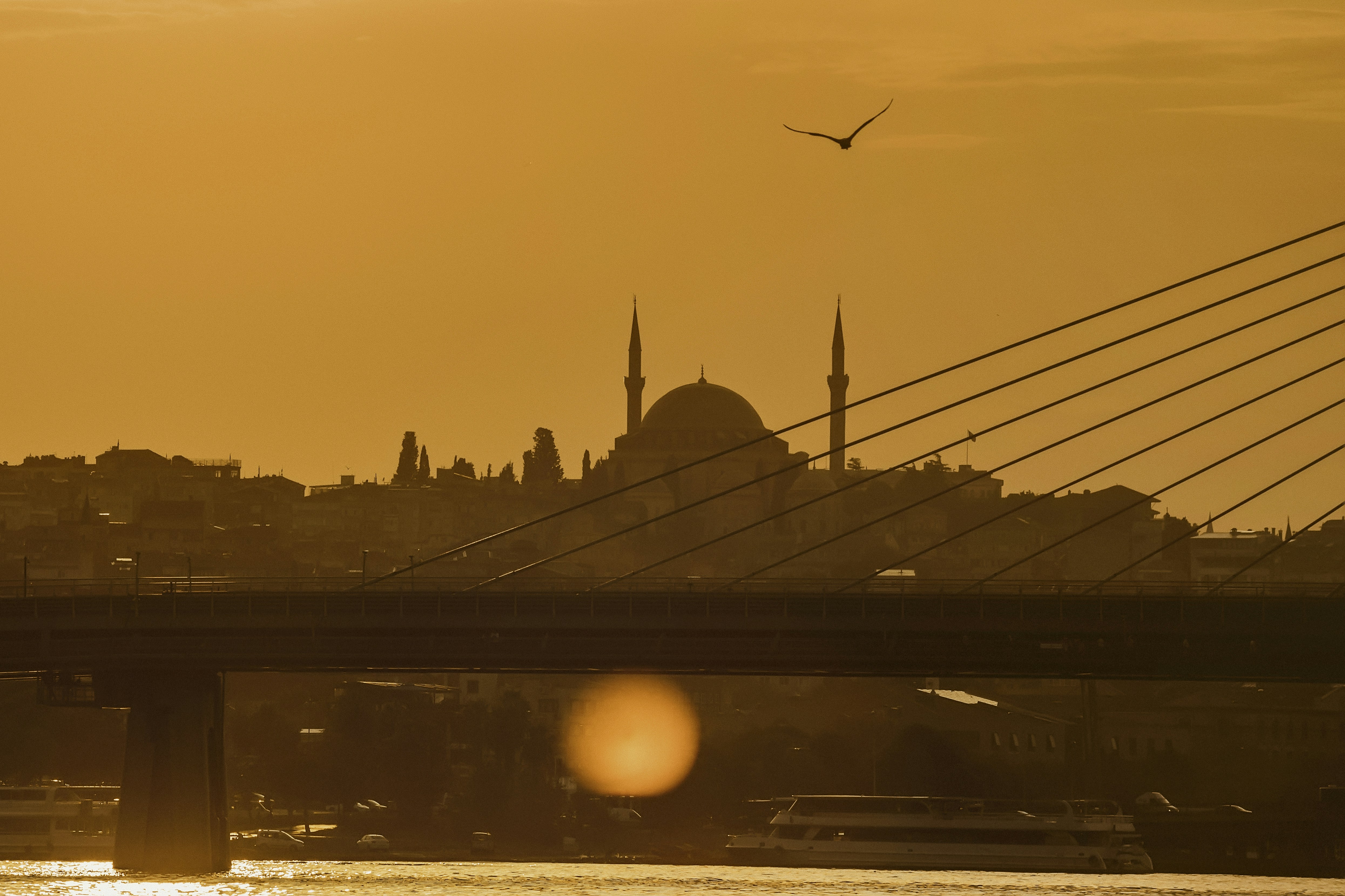Dusk Silhouette: Mosque Minarets Behind a Cable-Stayed Bridge at Sunset