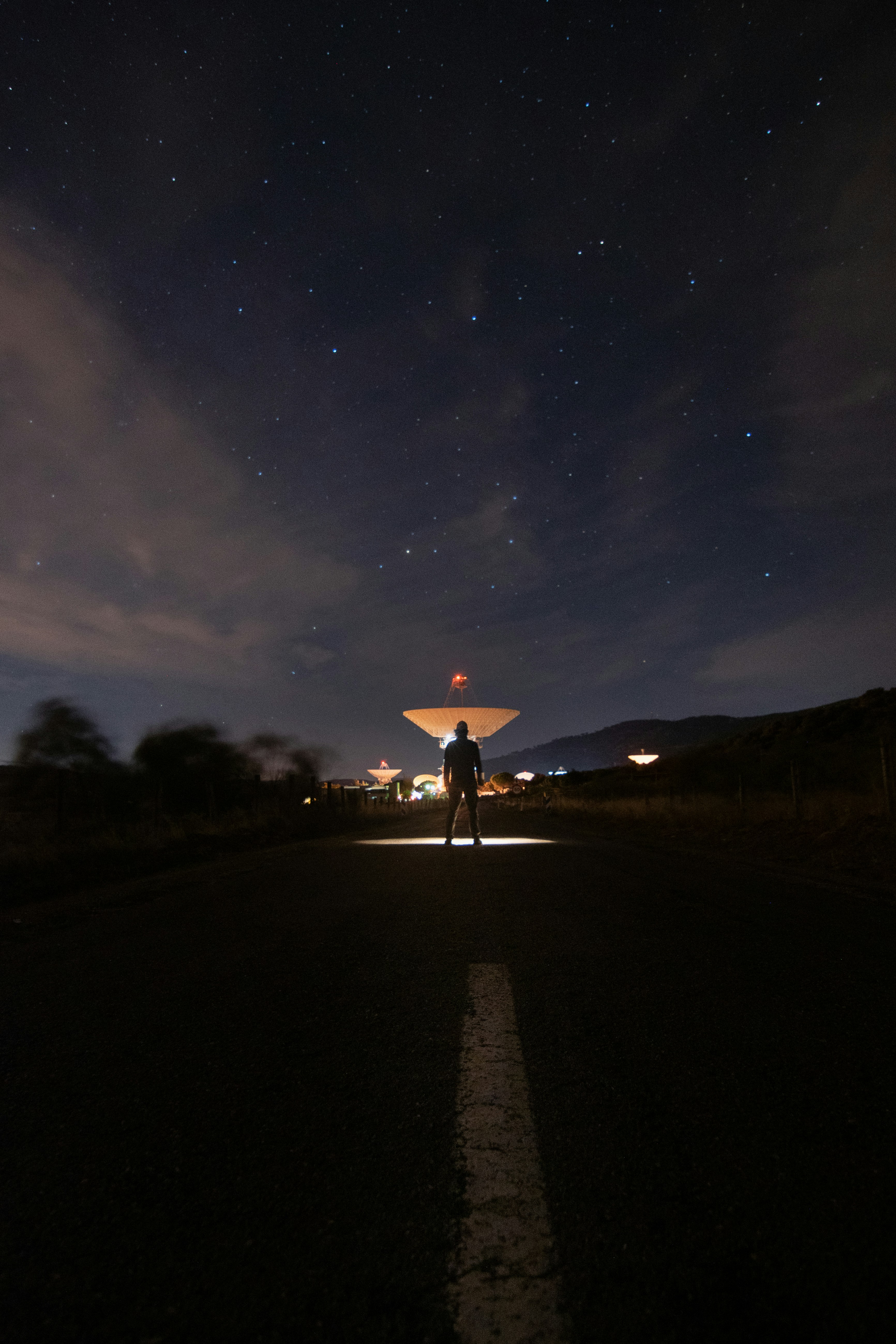 Lone Silhouette on a Starry Highway Beneath a Curved Satellite Glow